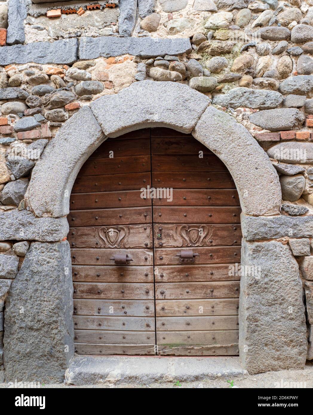 Old medieval arched entrance of an ancient stone house with wooden door ...