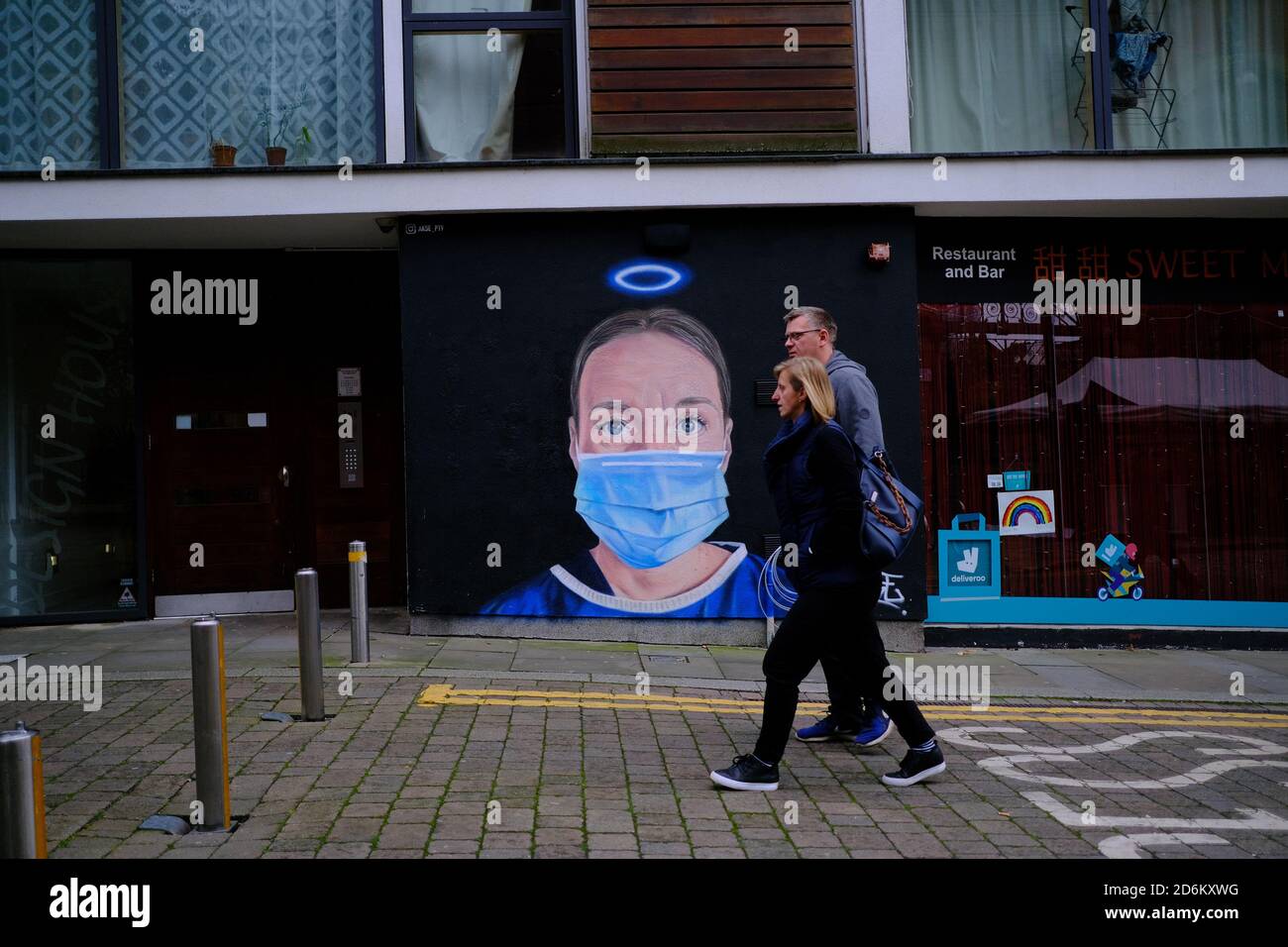 Couple of people without face masks passing by the mural in the High ...