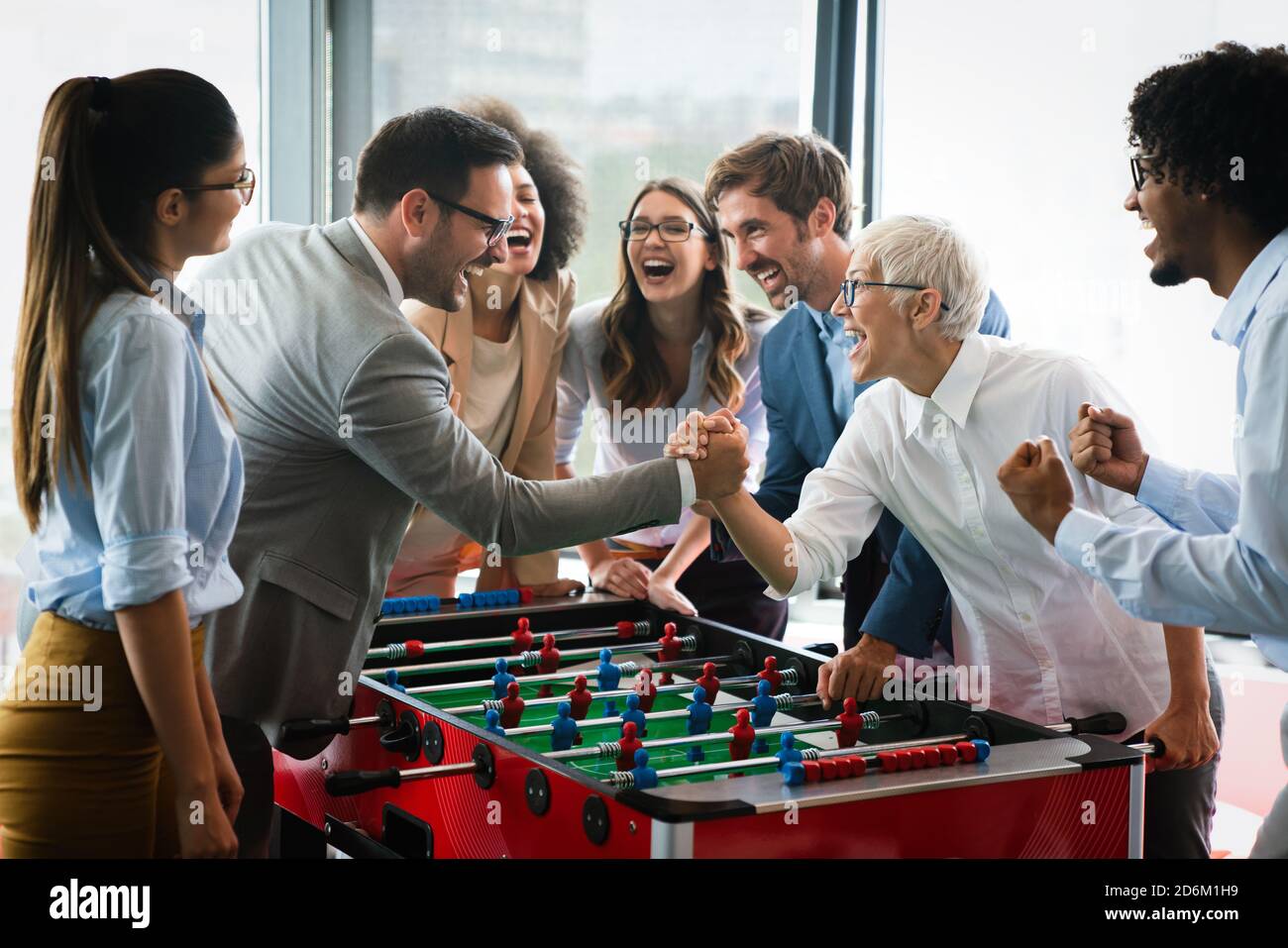 Coworkers playing table football on break from work Stock Photo - Alamy
