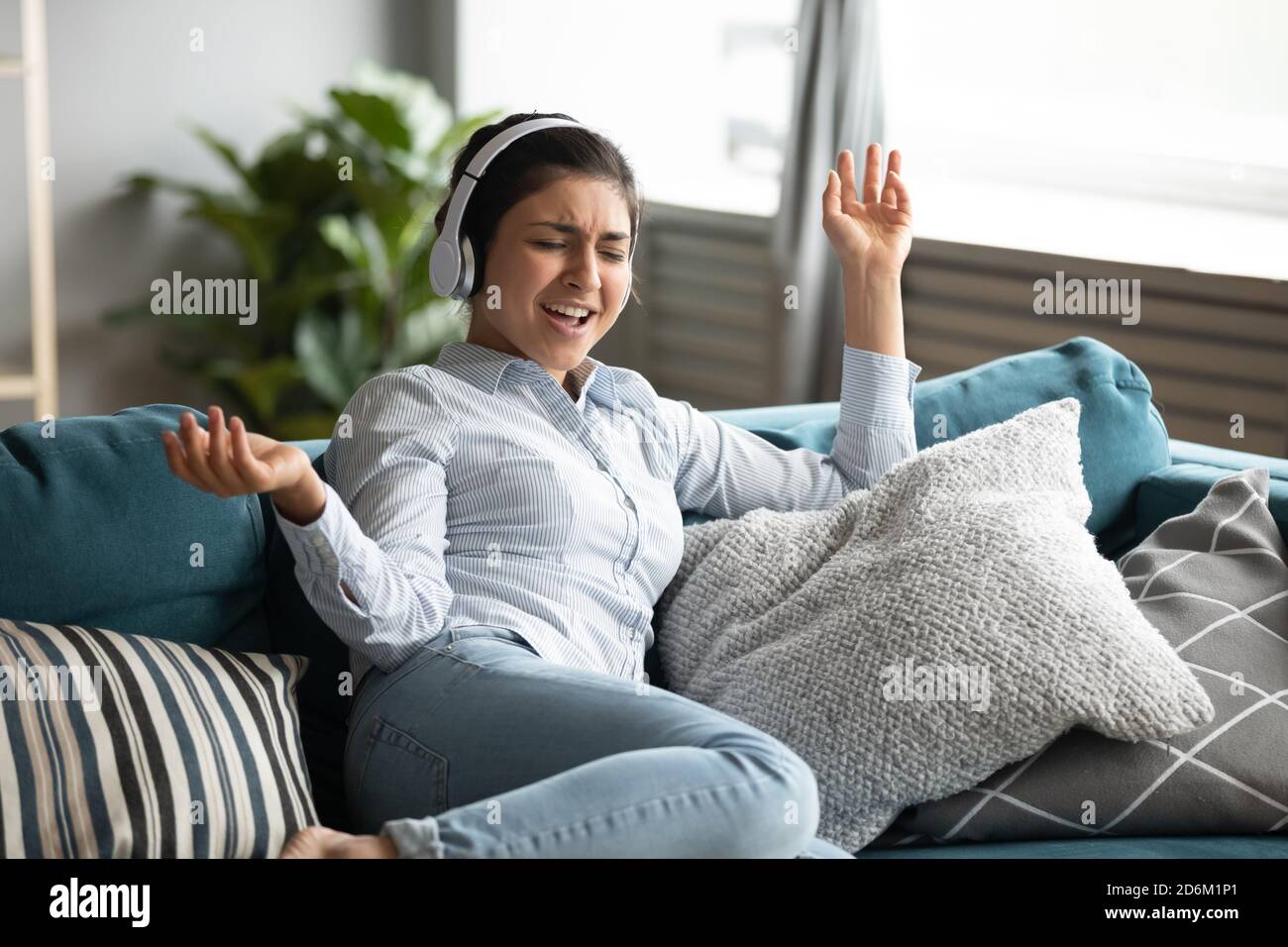 Indian woman wear headphones sing song relaxing on sofa Stock Photo - Alamy