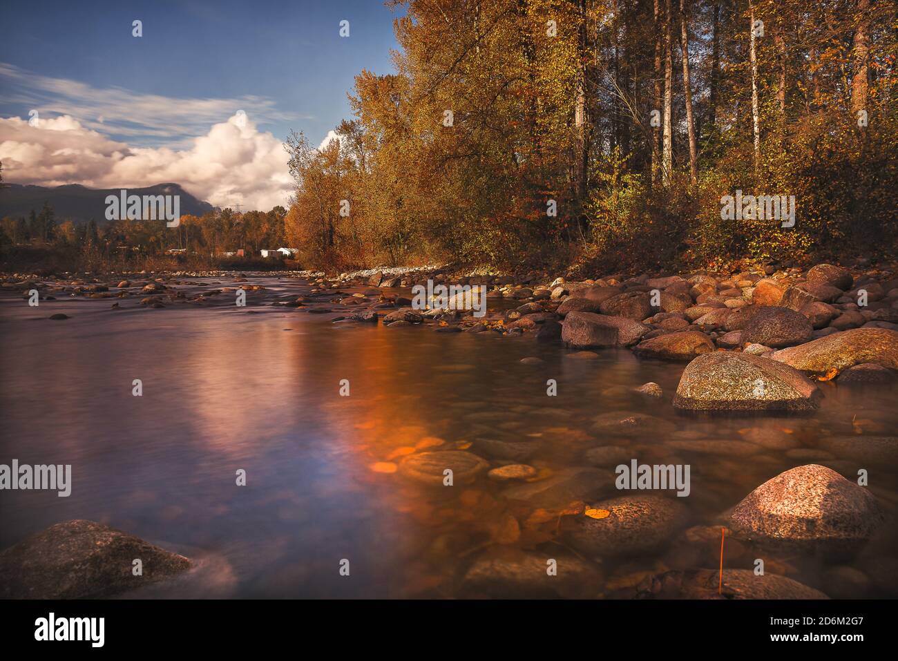 Low angle landscape view of a river lined with colorful trees in Autumn ...