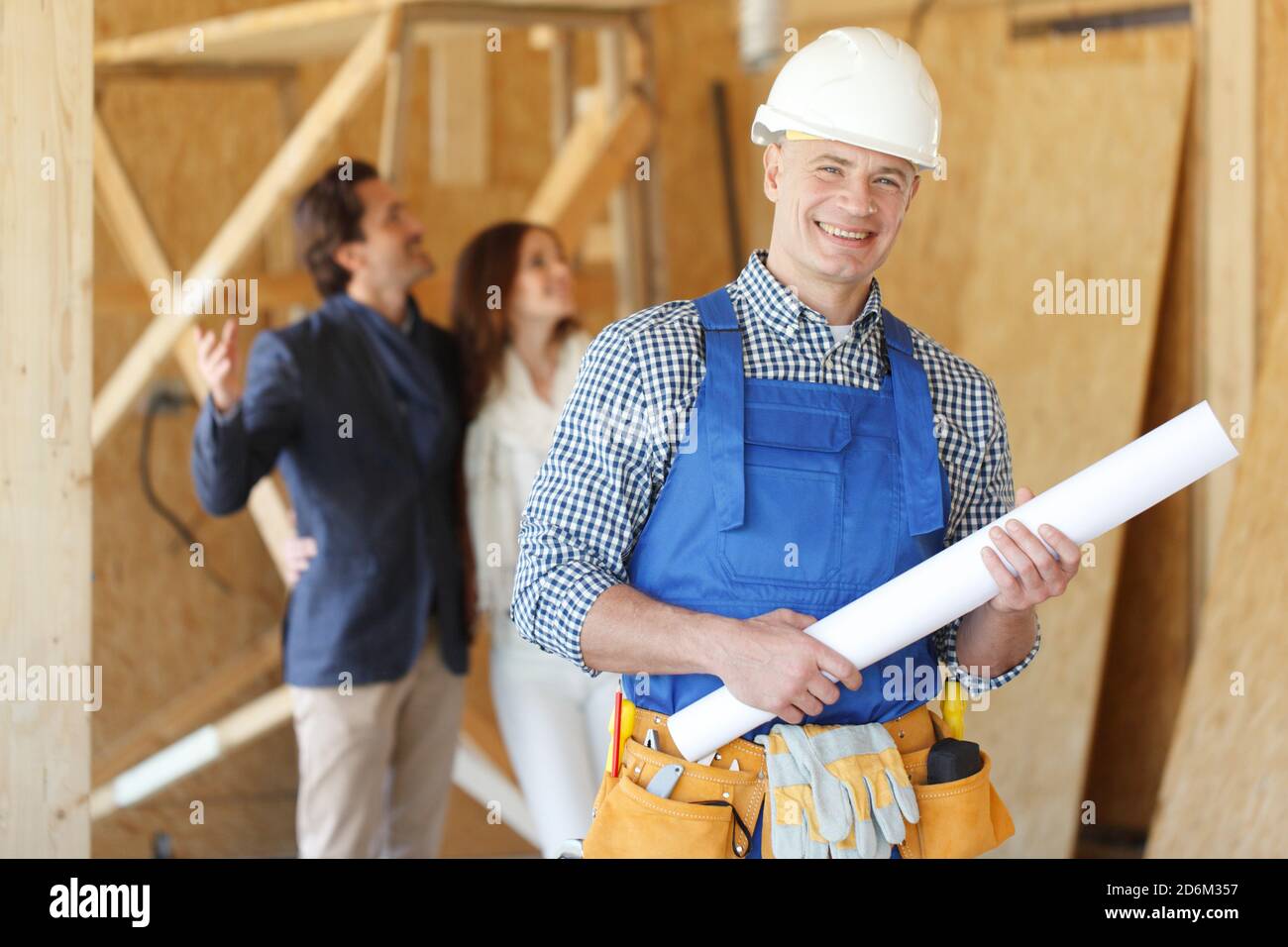 Foreman showing house design construction plan to a happy young couple ...