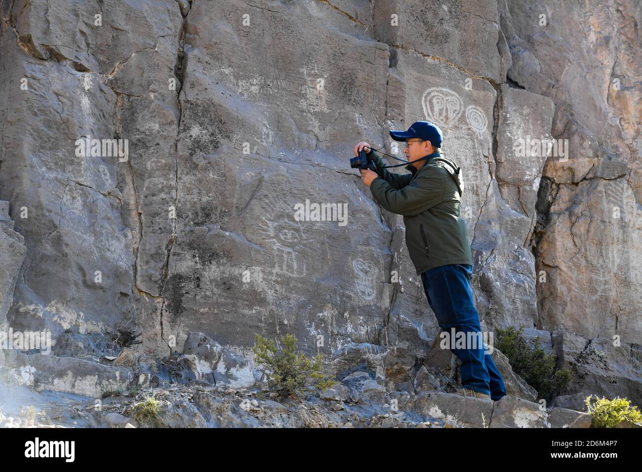 Wuhai. 17th Oct, 2020. An archeologist takes photo of rock drawings in ...