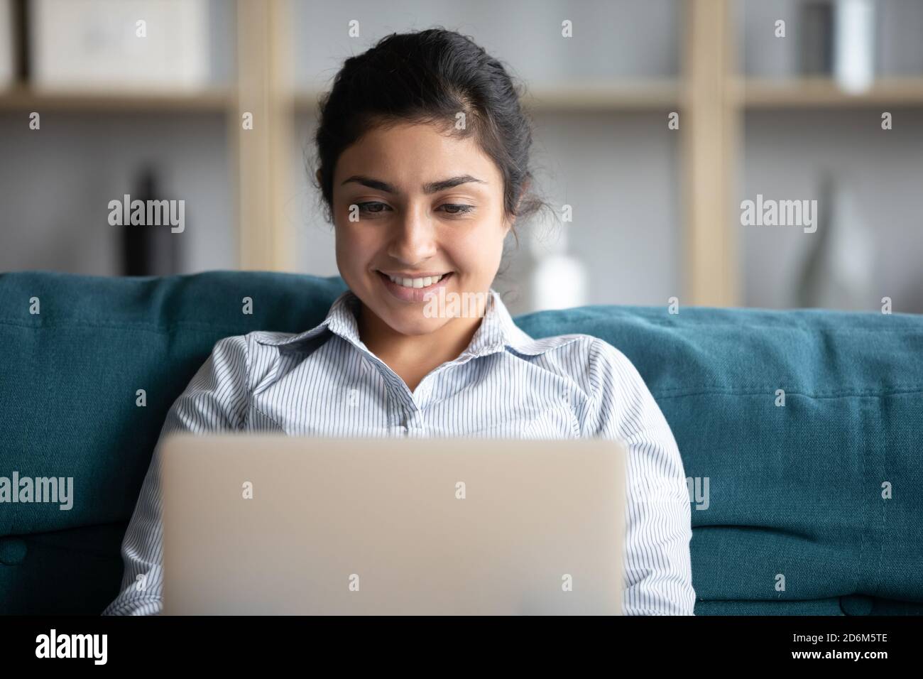 Indian girl using laptop seated on comfy couch at home Stock Photo - Alamy