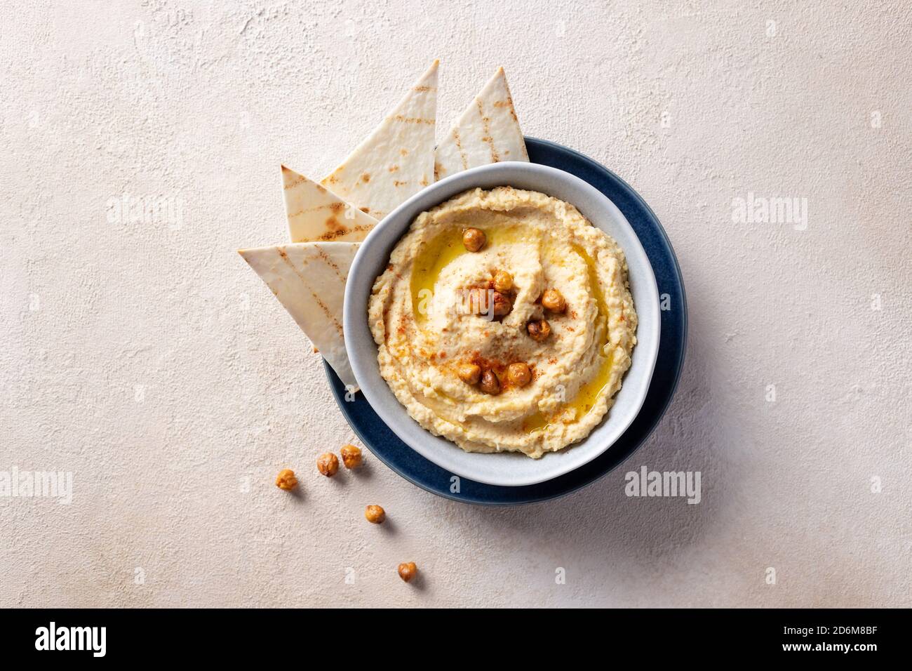 Hummus, chickpea dip in ceramic bowl over beige textured background ...