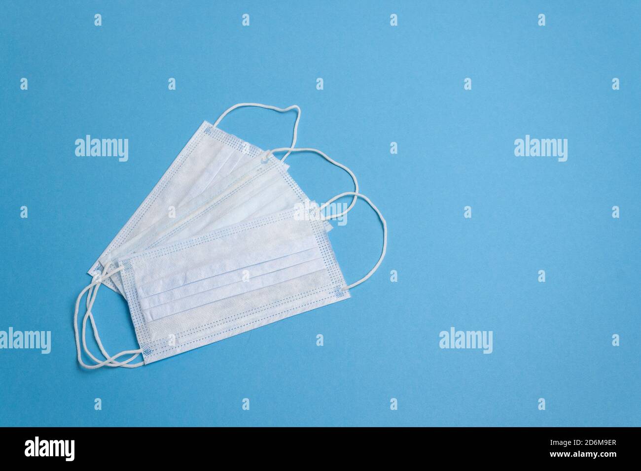 Three white reusable medical masks on blue background, isolated ...