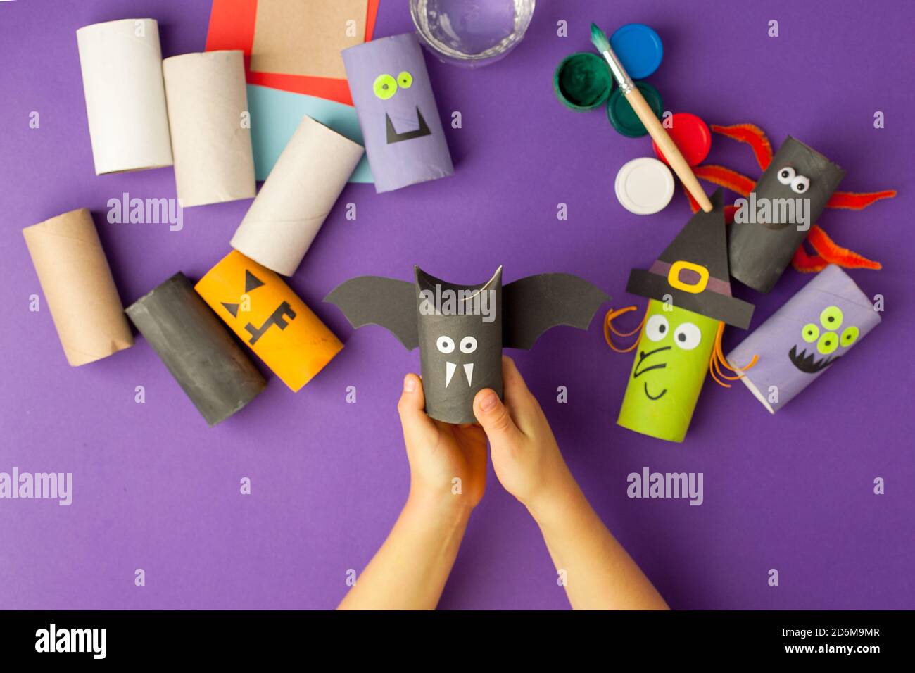 Kid hands holds a Halloween decorative toy from toilet roll. Boy mades ...