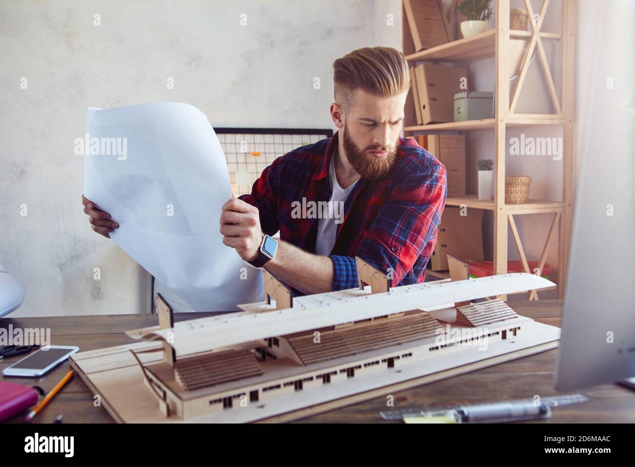 Engineer using drawing while looking wooden model of building on the ...