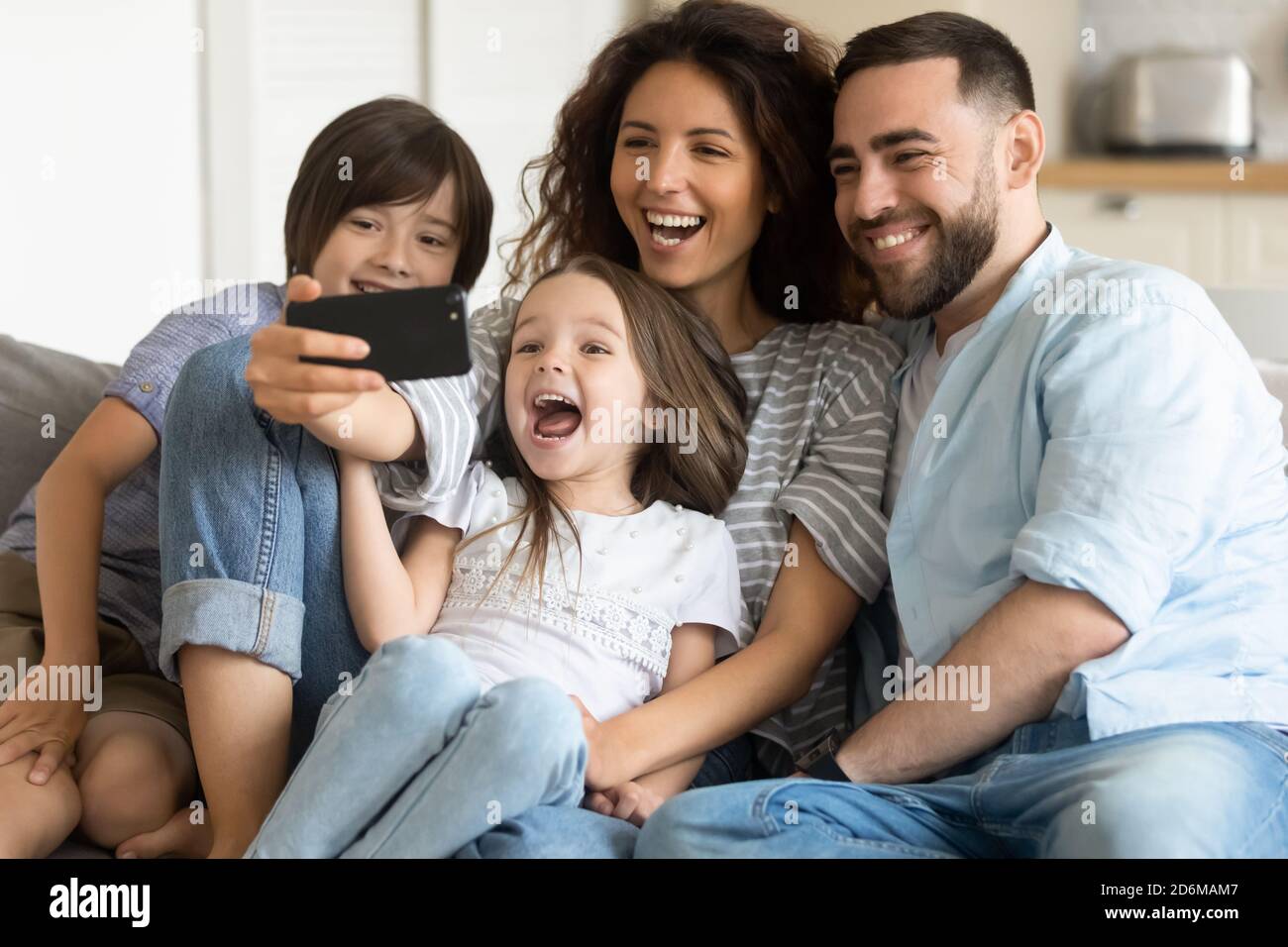 Overjoyed parents with two adorable kids posing for selfie together ...