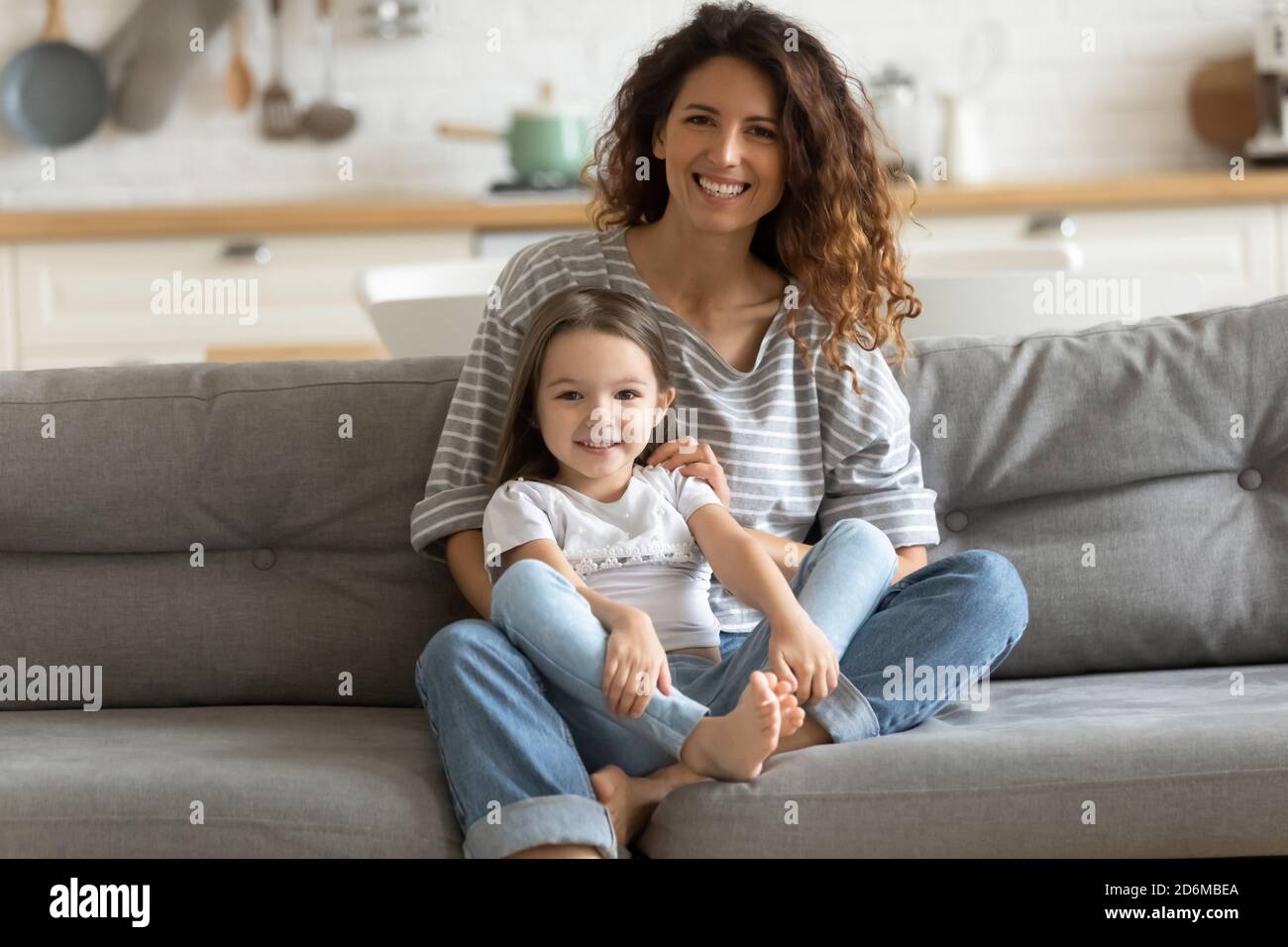 Portrait smiling young mother hugging little daughter, looking at camera Stock Photo - Alamy