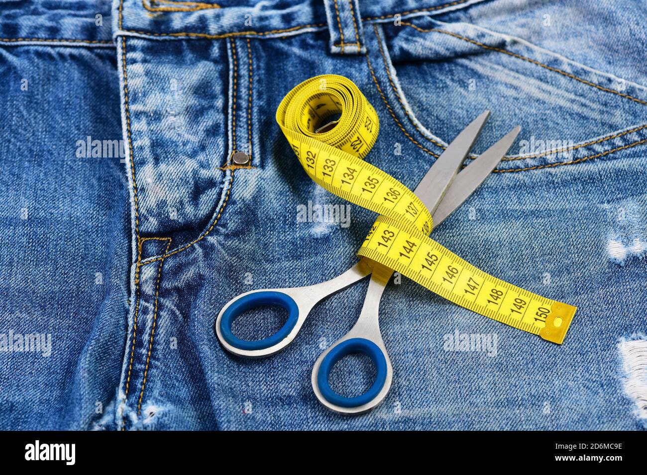Tailors tools on denim fabric, selective focus. Measure tape wound ...