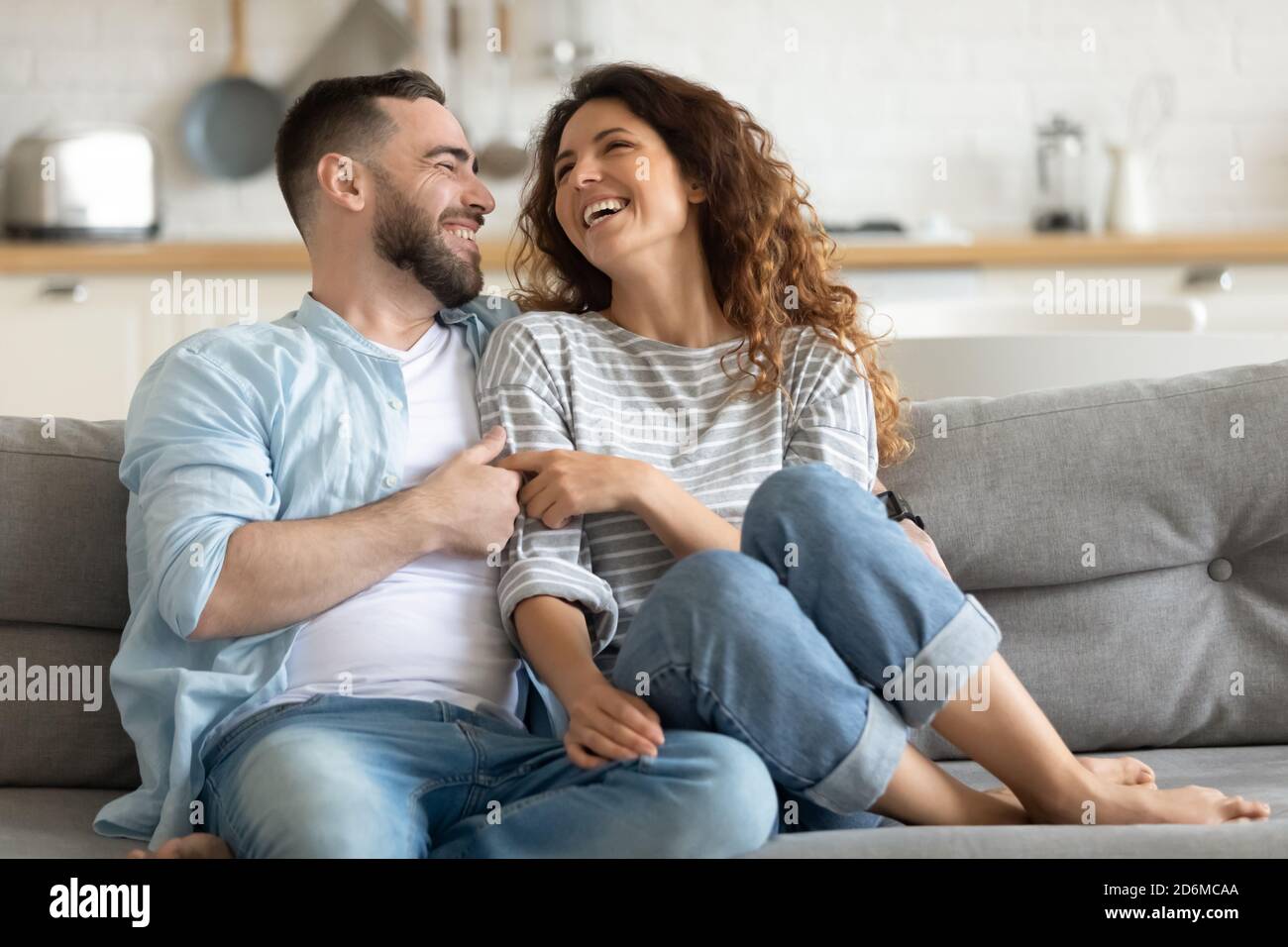 Happy married young couple hugging, sitting on couch together Stock ...