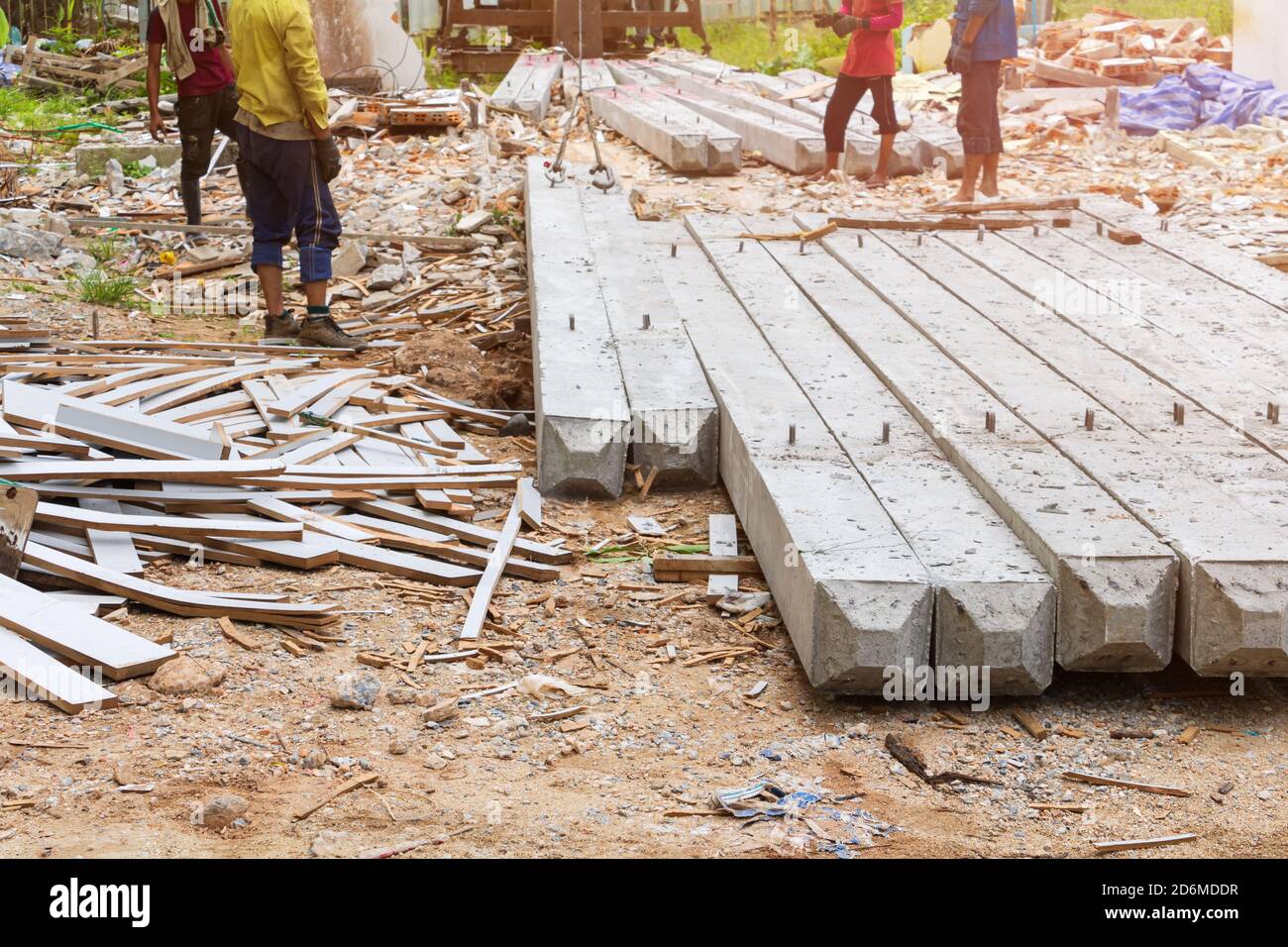 worker move pile concrete pillars on ground by sling in construction ...