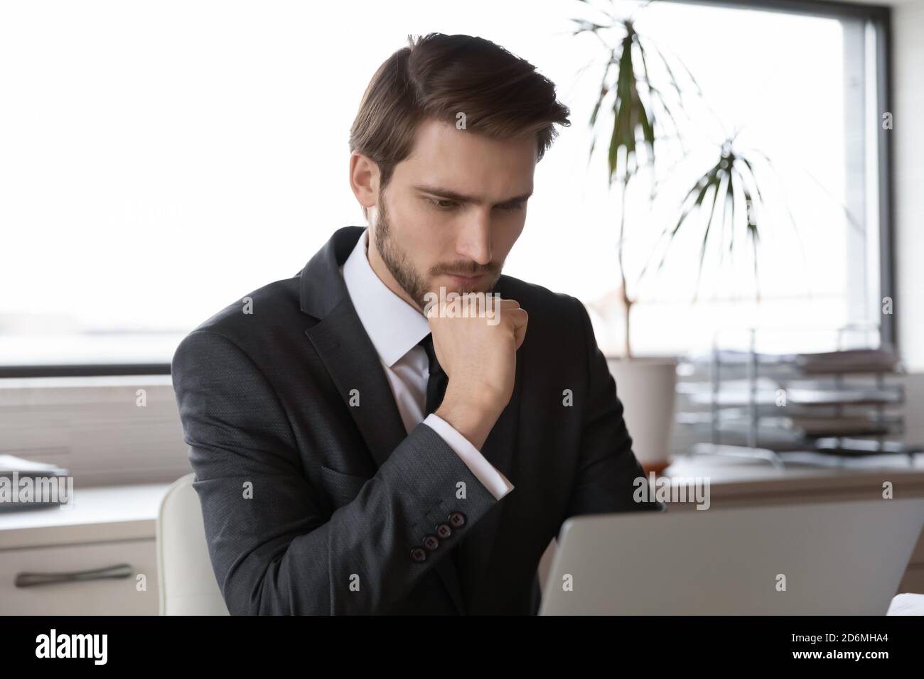 Focused young smart businessman looking at laptop screen Stock Photo ...