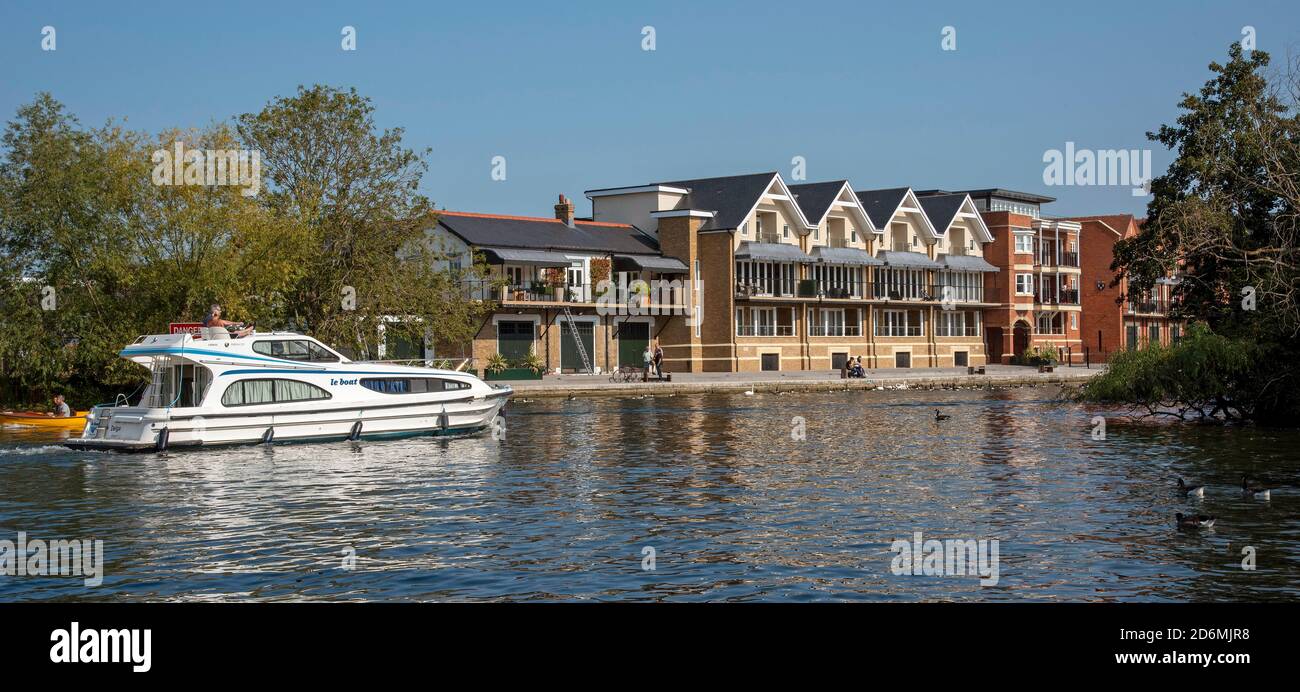 Eton, Buckinghamshire, England, UK. 2020. Cabin cruiser passing modern ...