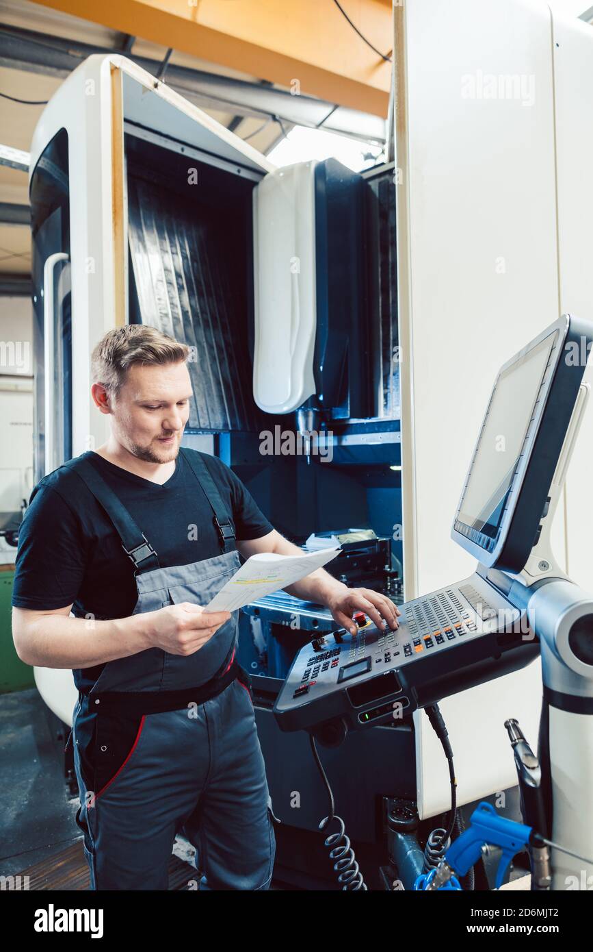Worker in industrial workshop programming a cnc machine Stock Photo - Alamy