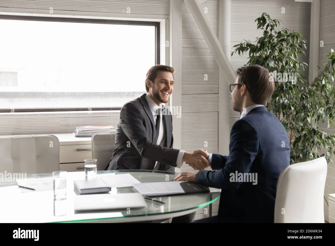 Happy young manager shaking hands with leader Stock Photo - Alamy