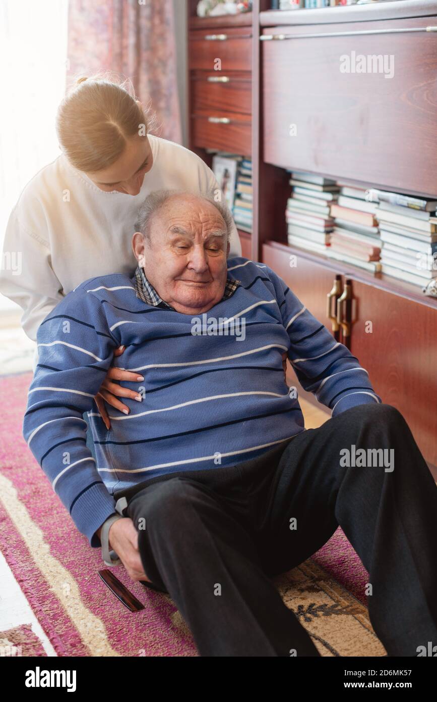 Nurse helping senior man getting up after he fell Stock Photo - Alamy