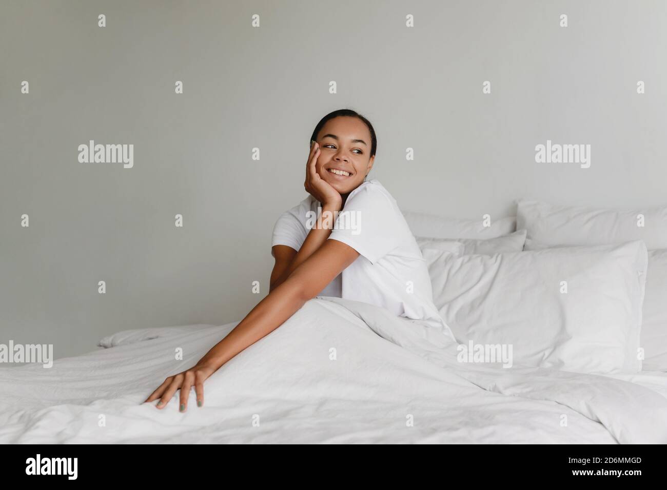 Beautiful smiling african american woman sitting on bed Stock Photo - Alamy