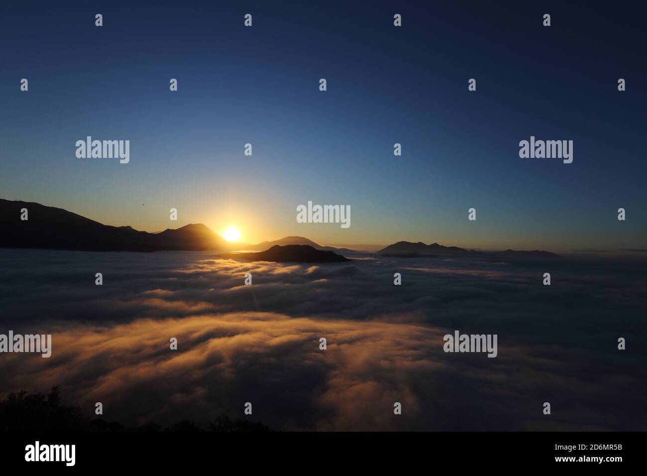 new day - the sun at dawn with fog and backlit mountains Stock Photo ...
