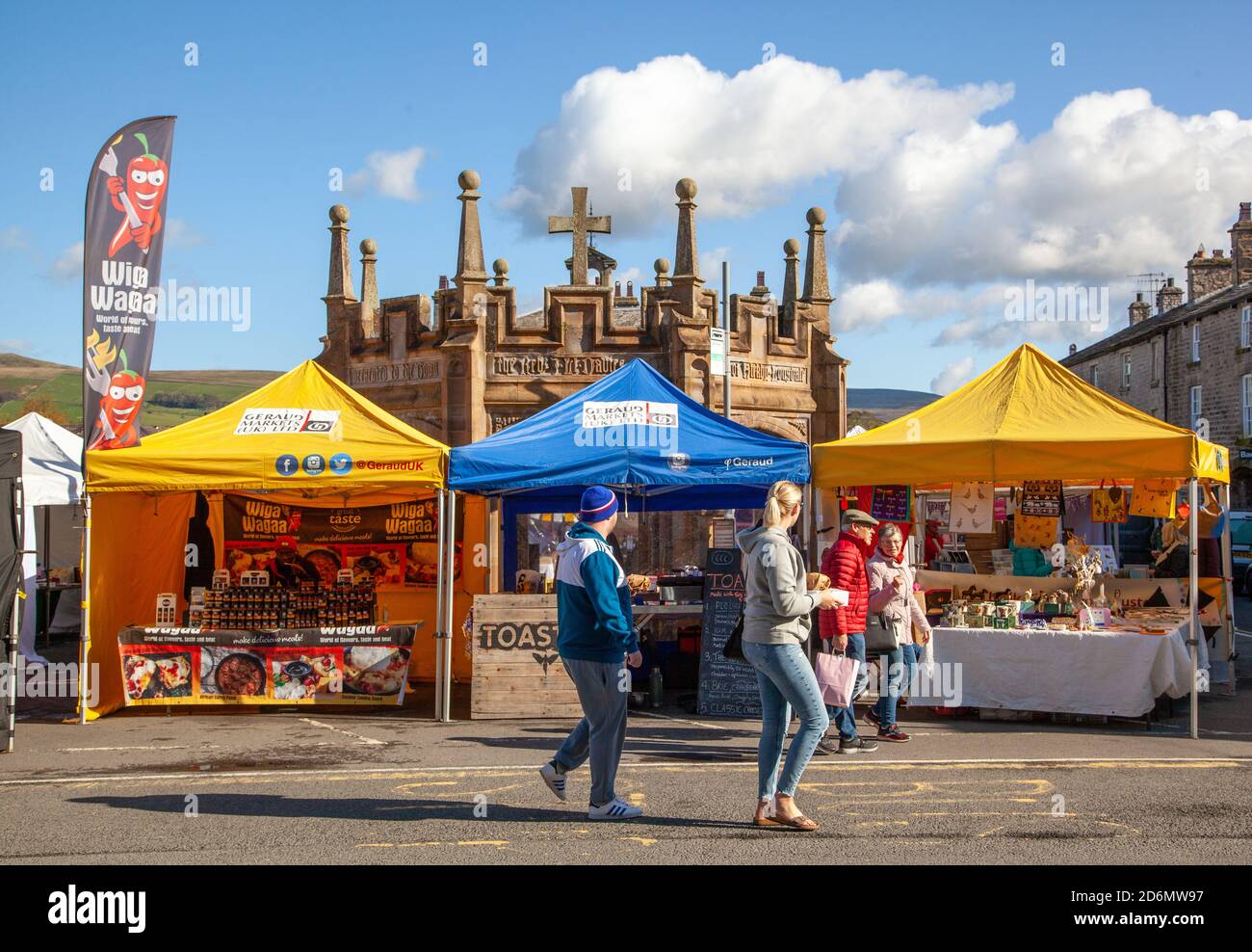 People walking past market stalls in the market square in the Cumbrian ...