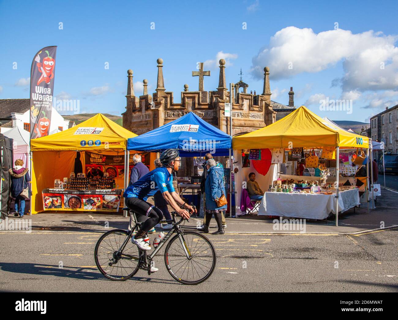 Man cycling past market stalls in the market square in the Cumbrian ...