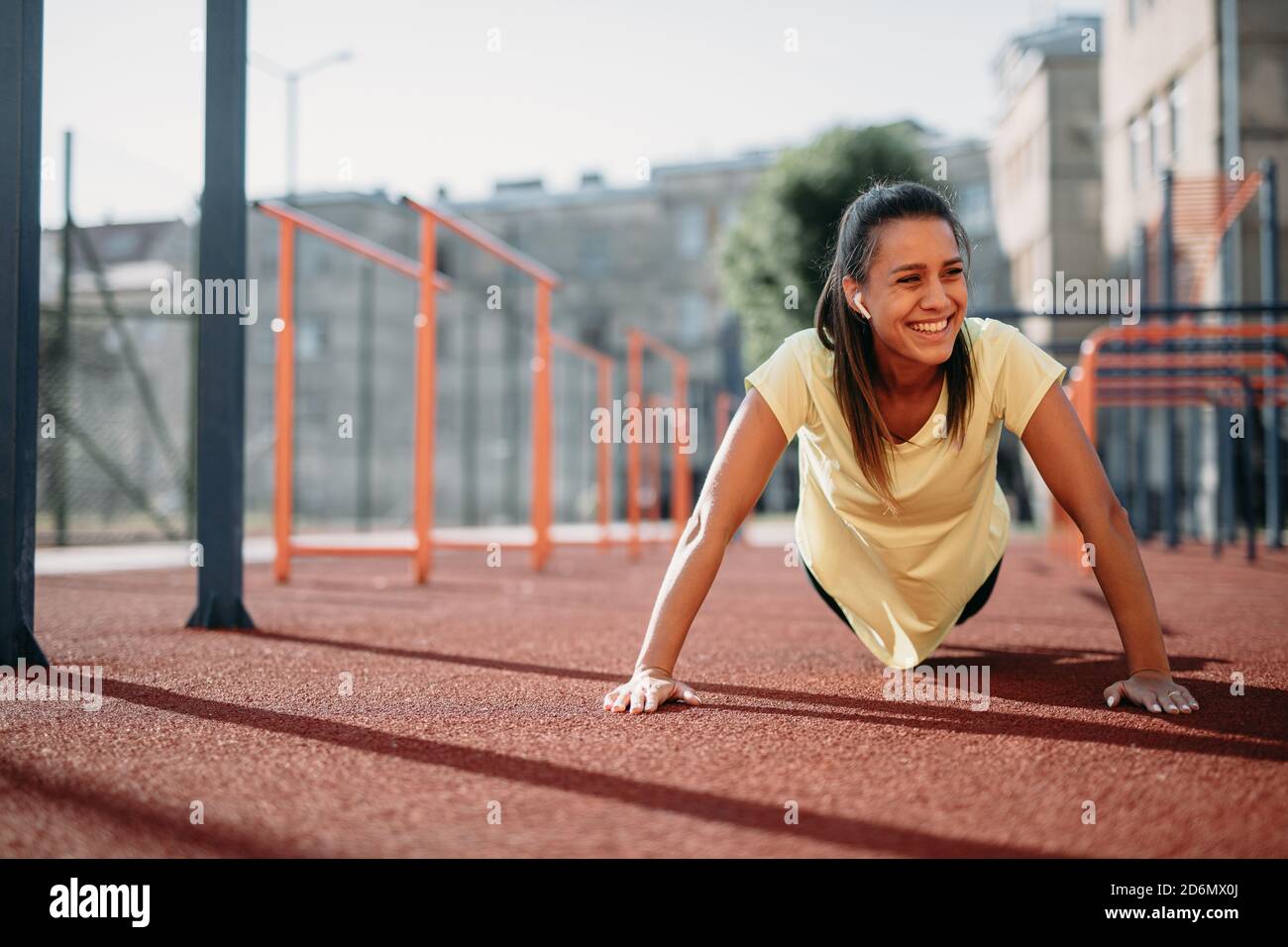 Smiling female doing push ups at sports ground Stock Photo - Alamy