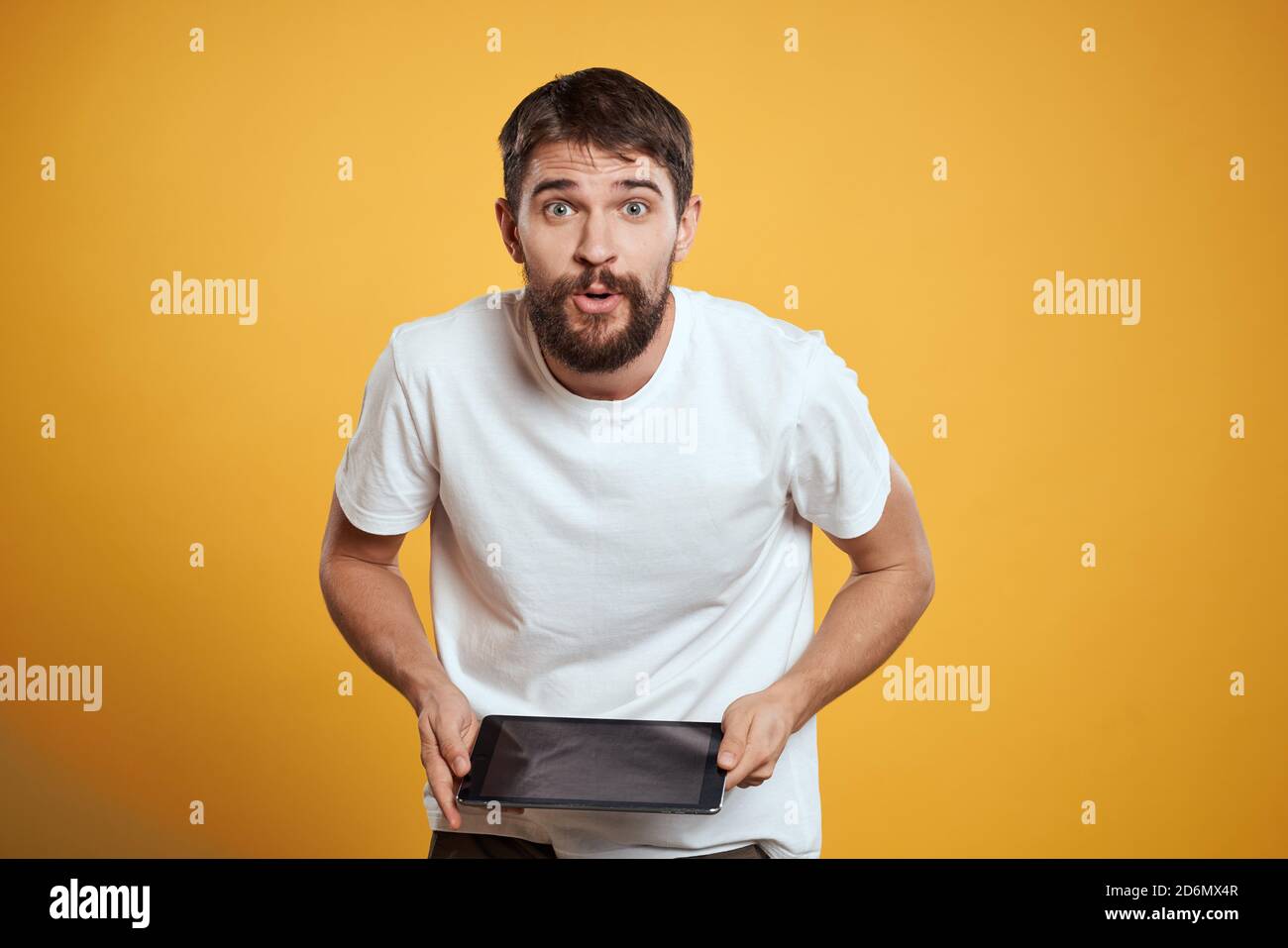 Man with a tablet on a yellow background in a white t-shirt new ...