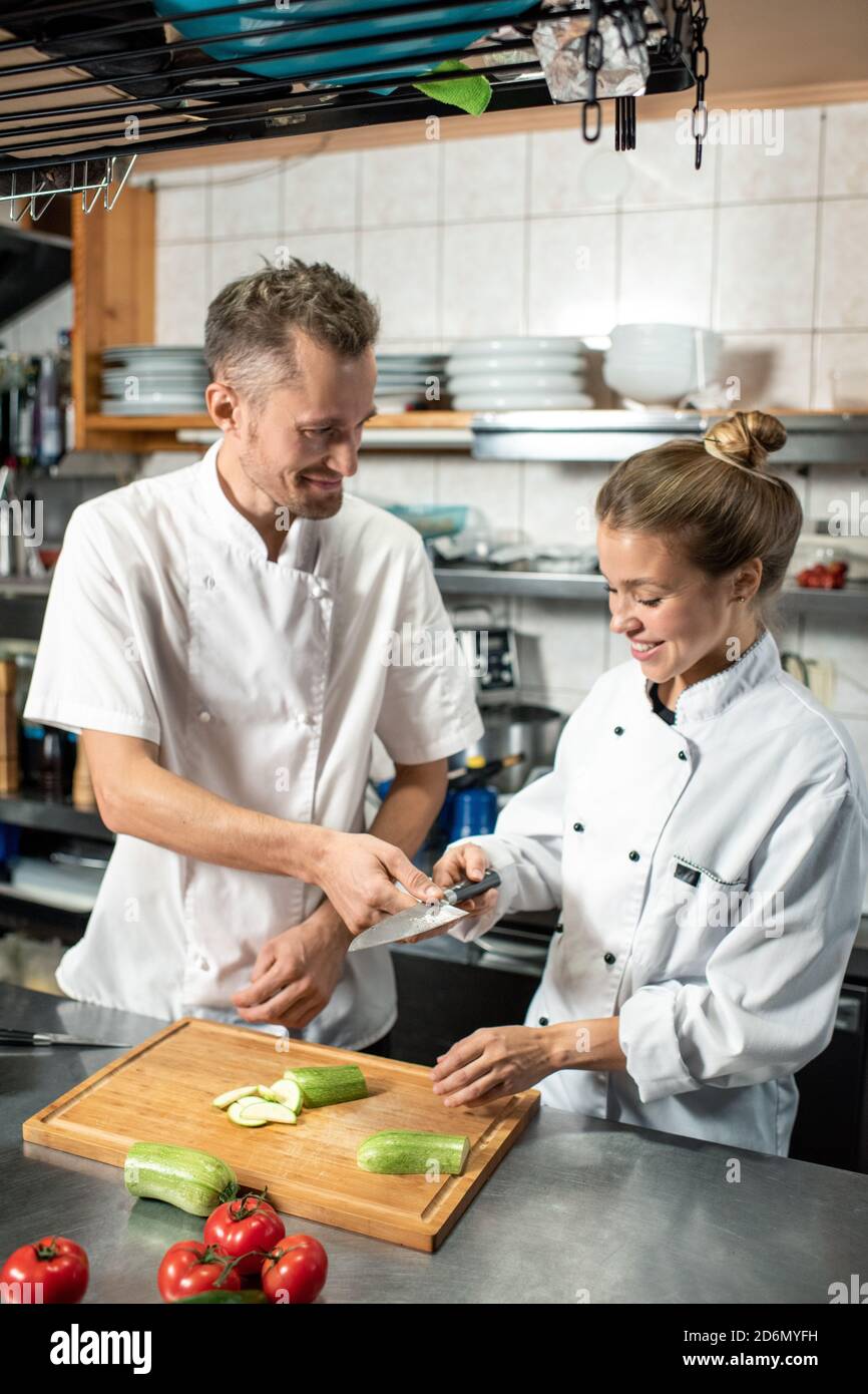 Happy professional chef passing sharp knife to trainee slicing fresh ...