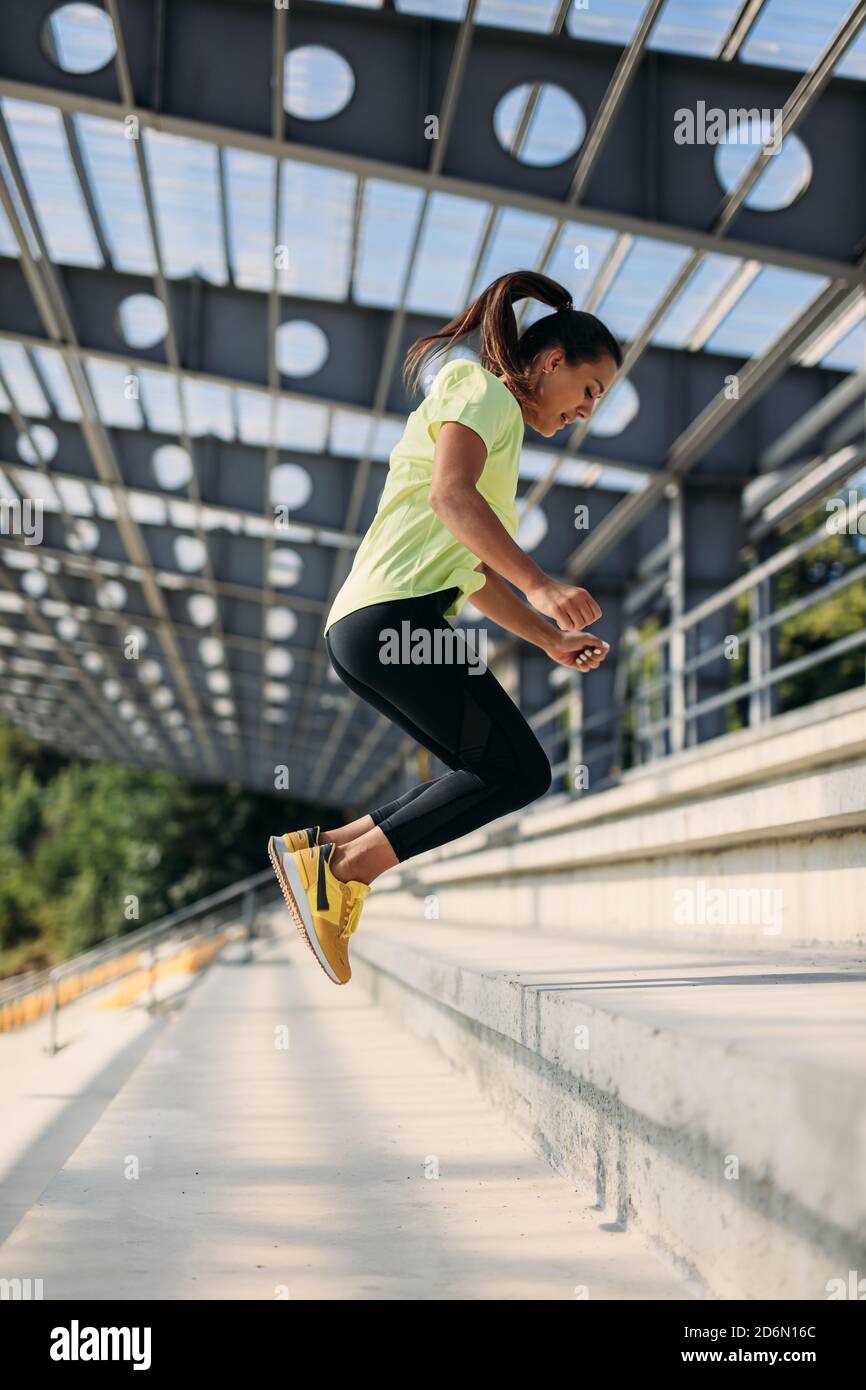 Female athlete in activewear jumping on stairs Stock Photo - Alamy