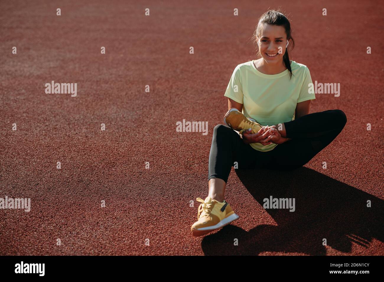 Smiling female doing flexibility exercises on fresh air Stock Photo - Alamy