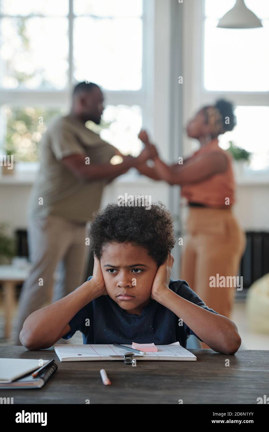 Annoyed little boy covering his ears by hands while his parents having ... Annoyed little boy covering his ears by hands while his parents having ...