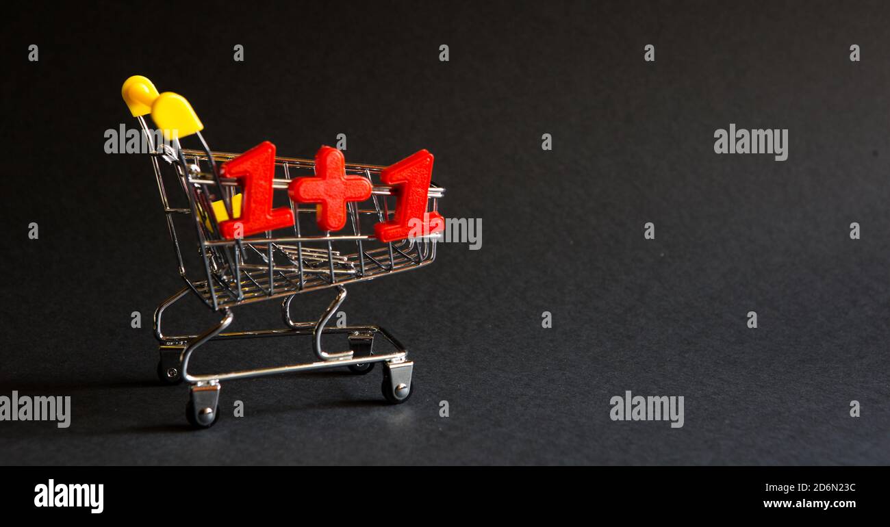 Shopping cart and the numbers "1+1" on a black background. Black Friday ...