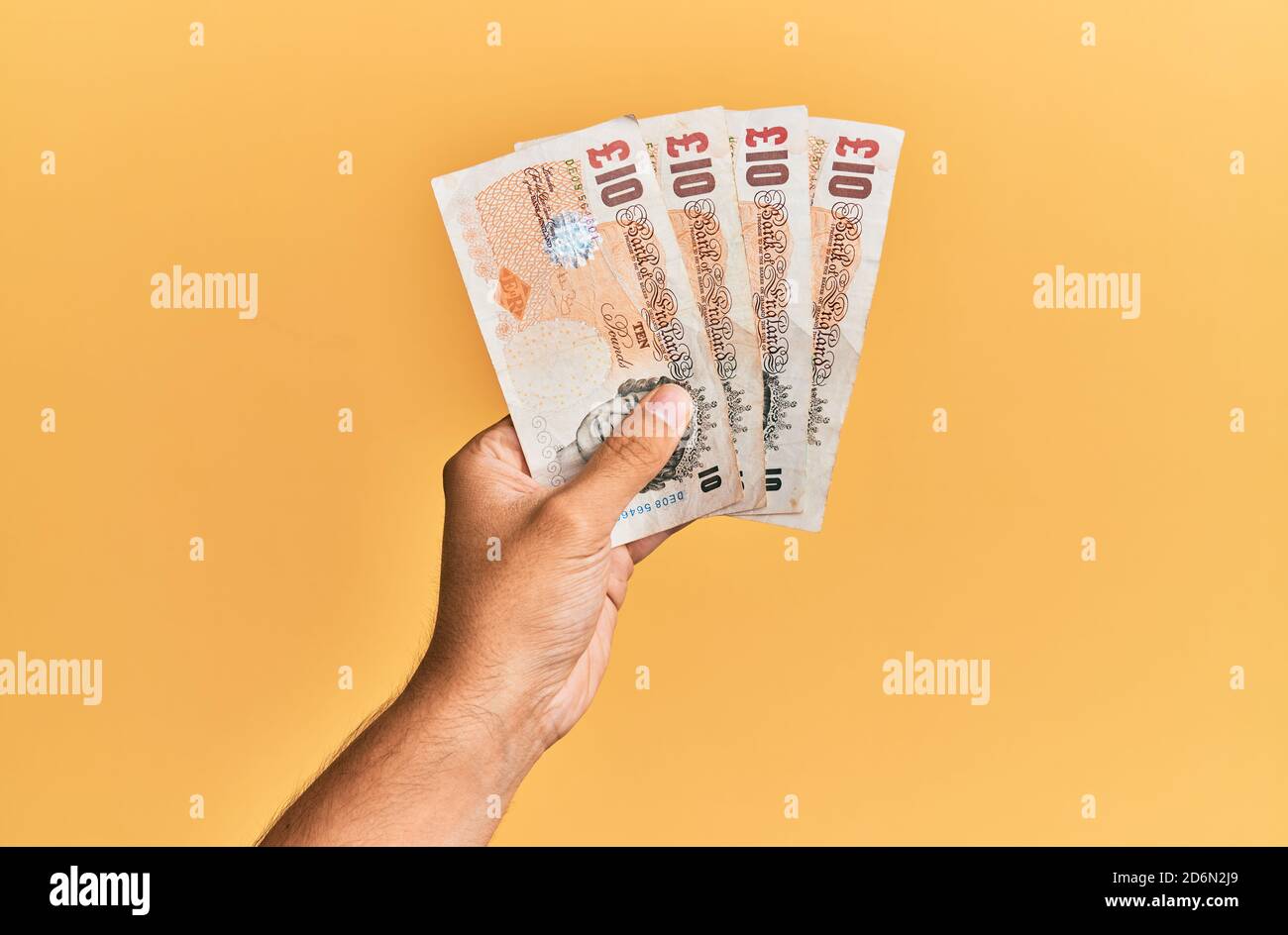 Hand of hispanic man holding uk 10 pounds banknotes over isolated ...