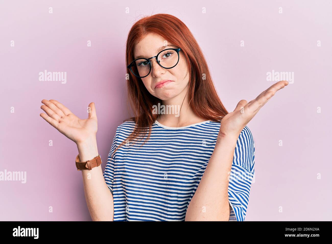 Young red head girl wearing casual clothes and glasses clueless and ...