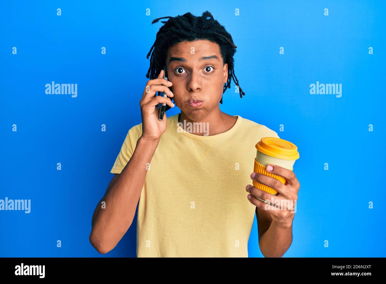 Young african american man using smartphone and drinking a cup of ...
