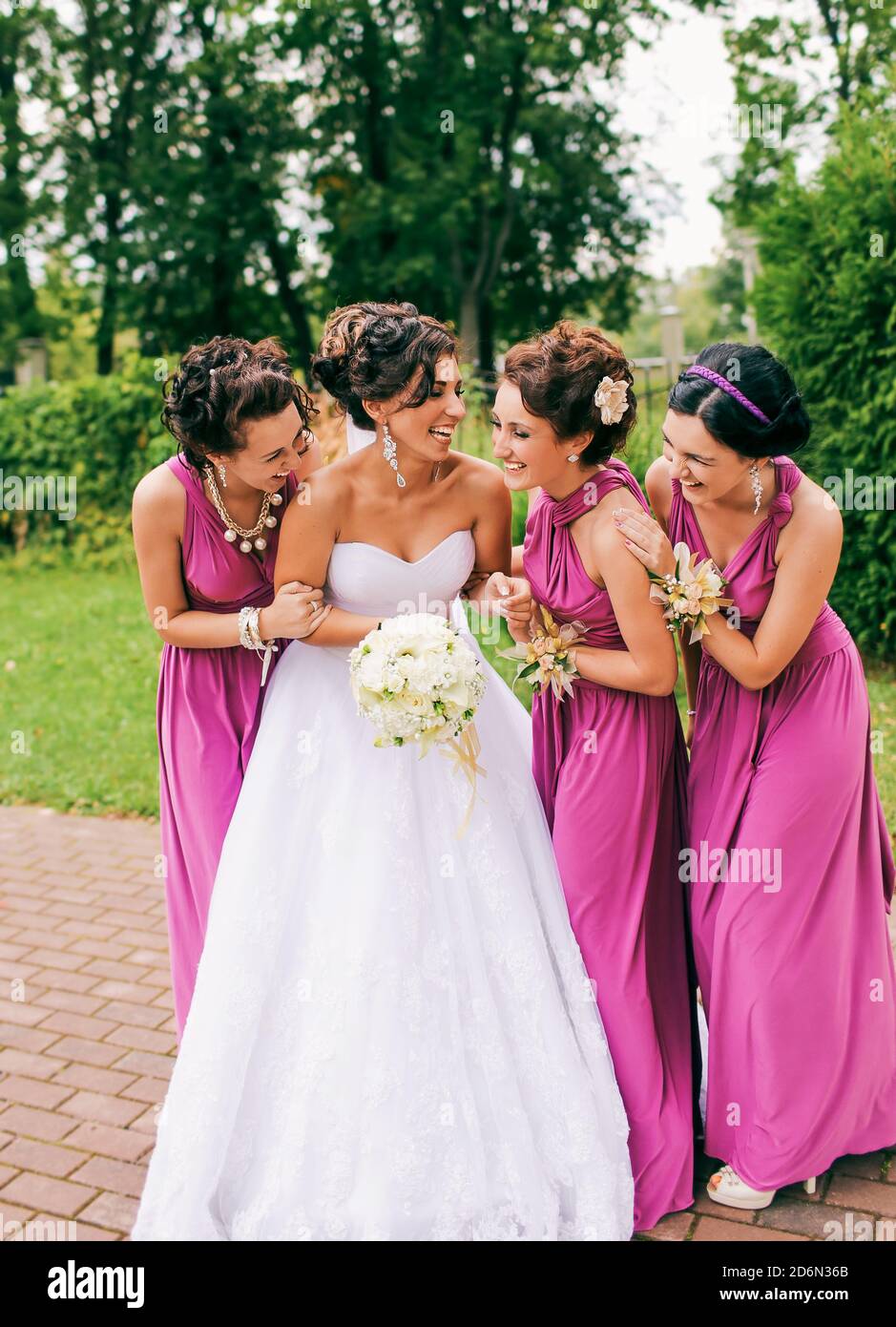 bridesmaids in pink dresses hug the bride and laugh at an Italian ...