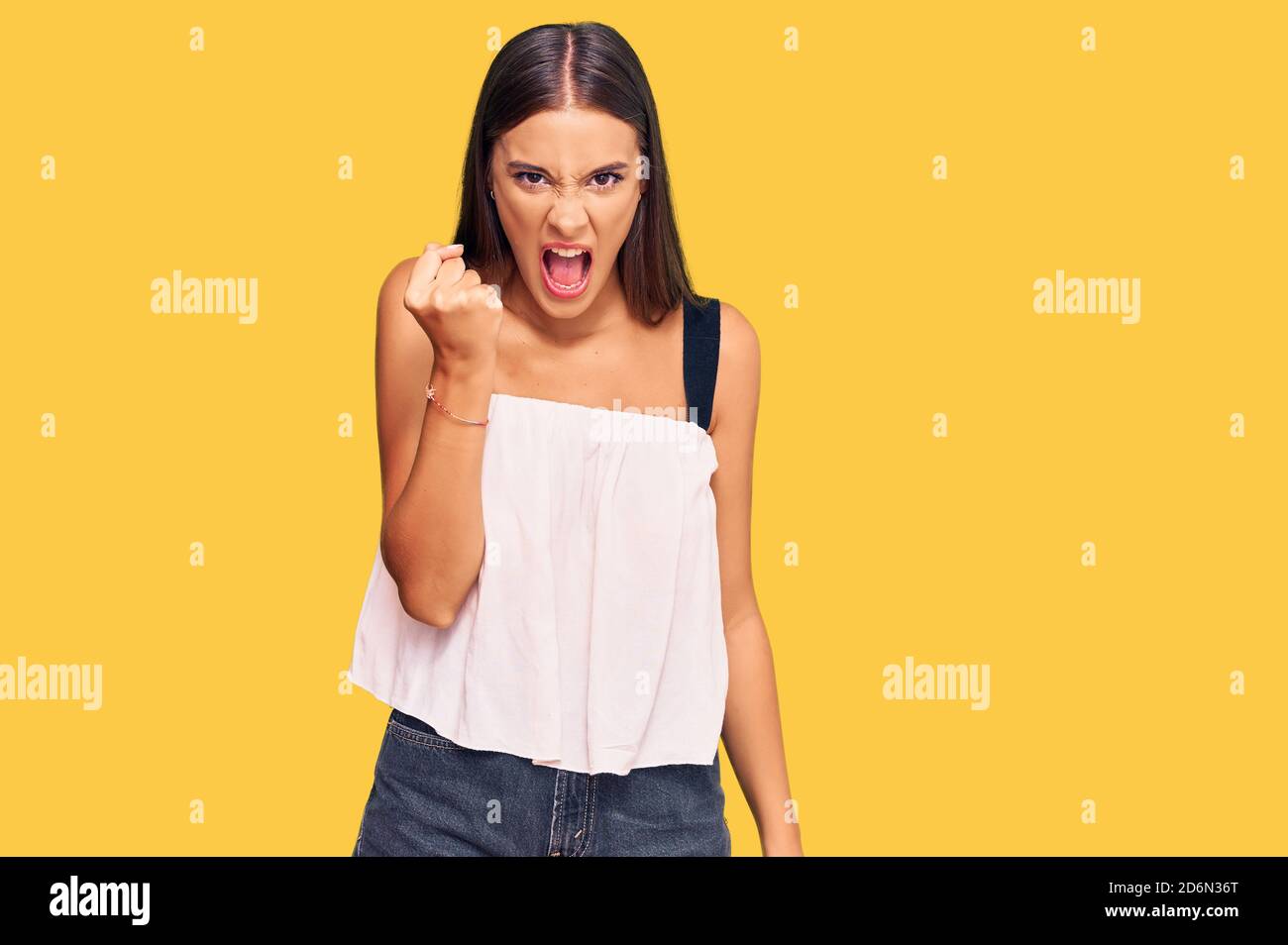 Young hispanic woman wearing casual clothes angry and mad raising fist ...