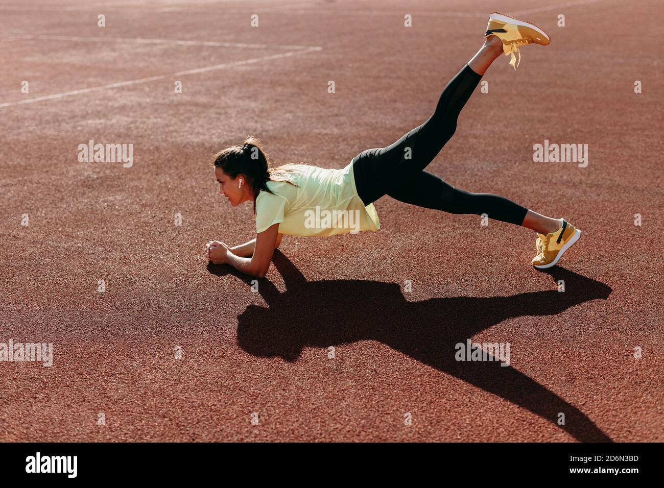 Strong active lady standing in plank position on red court Stock Photo ...