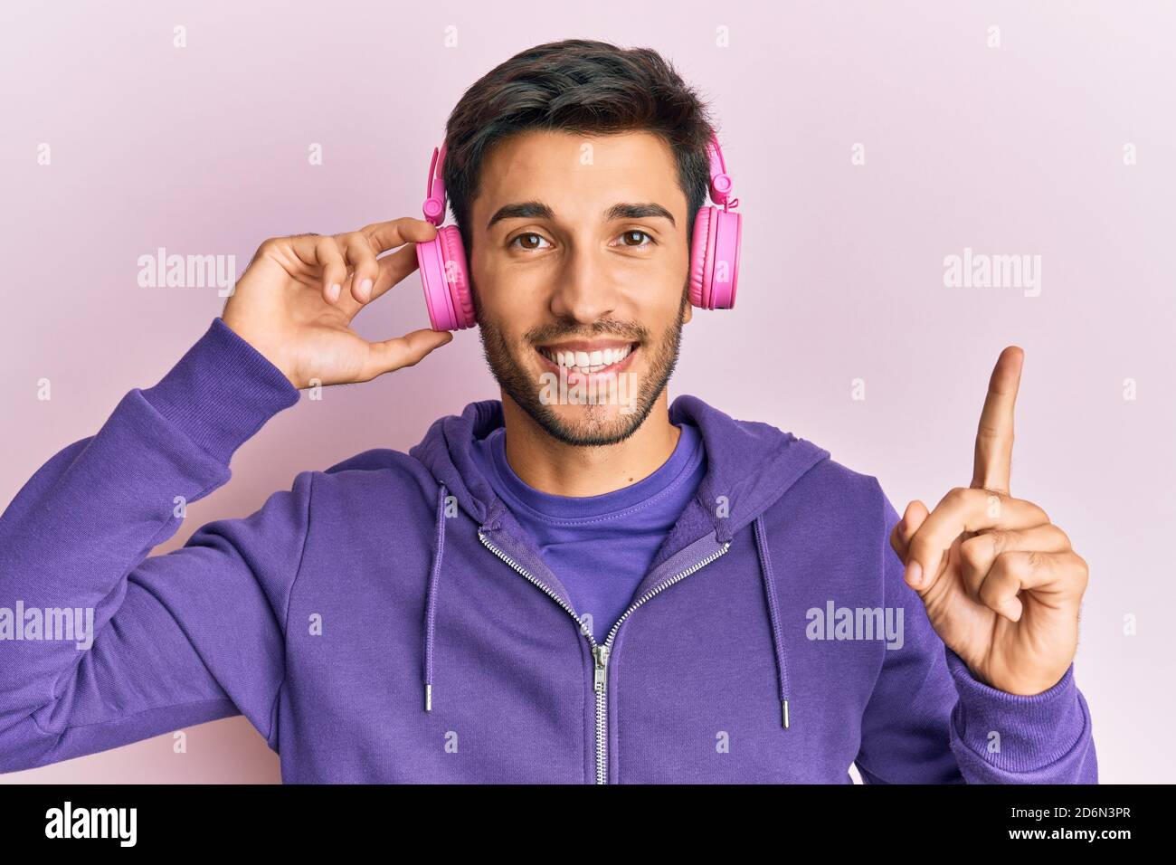 Young handsome man listening to music using headphones smiling with an ...