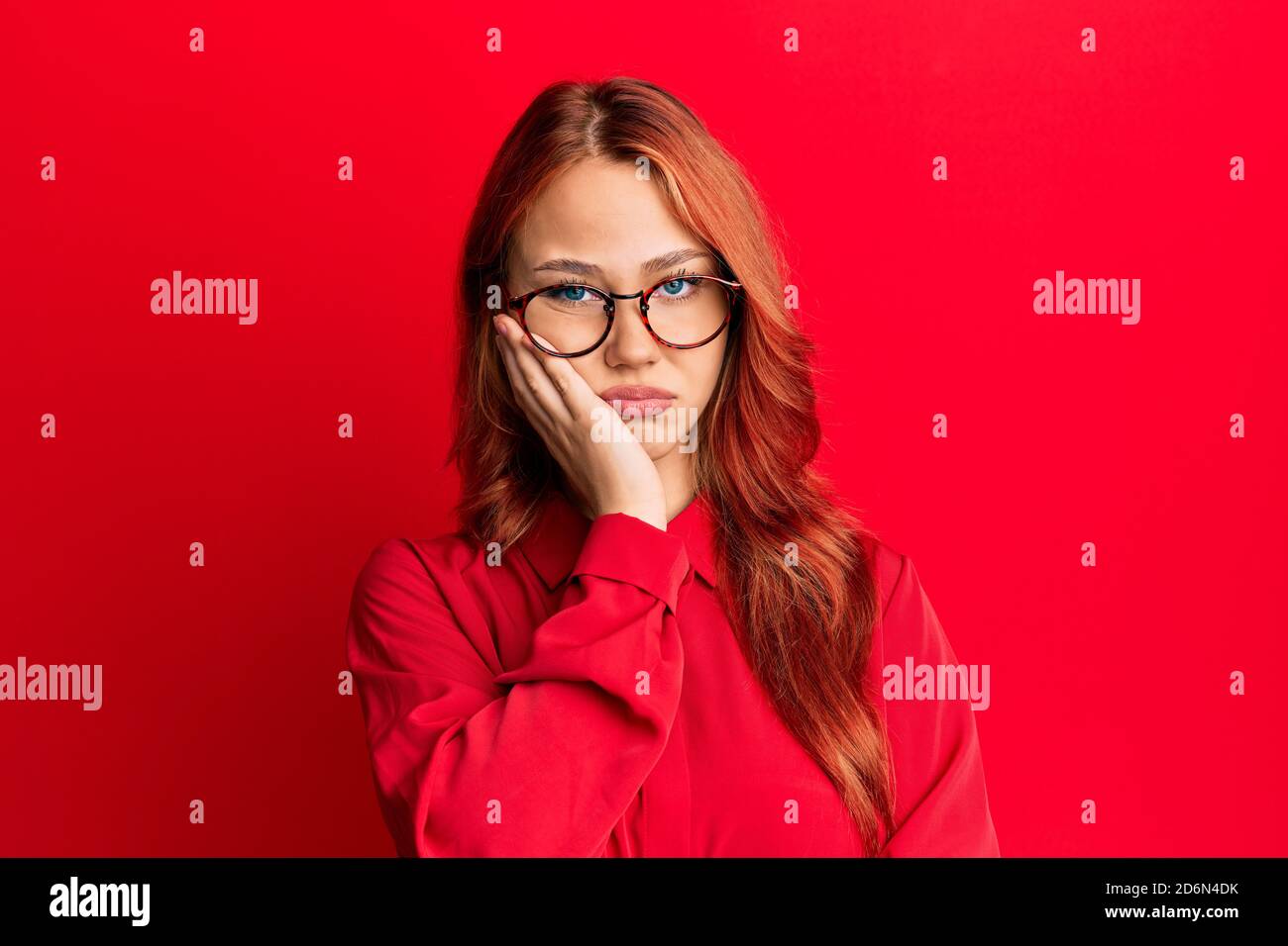 Young beautiful redhead woman wearing casual clothes and glasses over ...