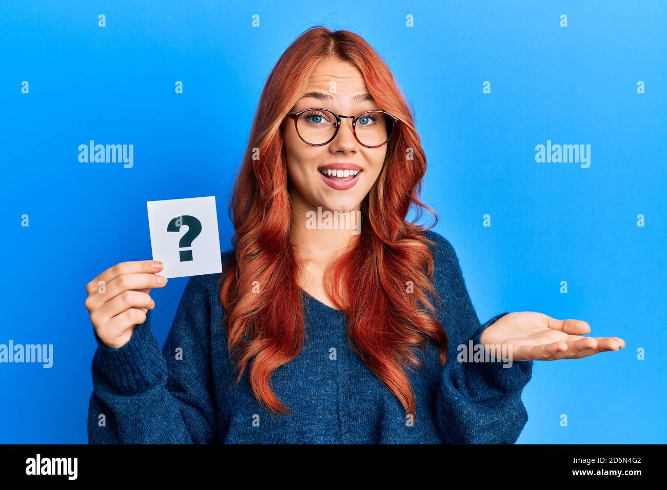 Young beautiful redhead woman holding question mark celebrating ...