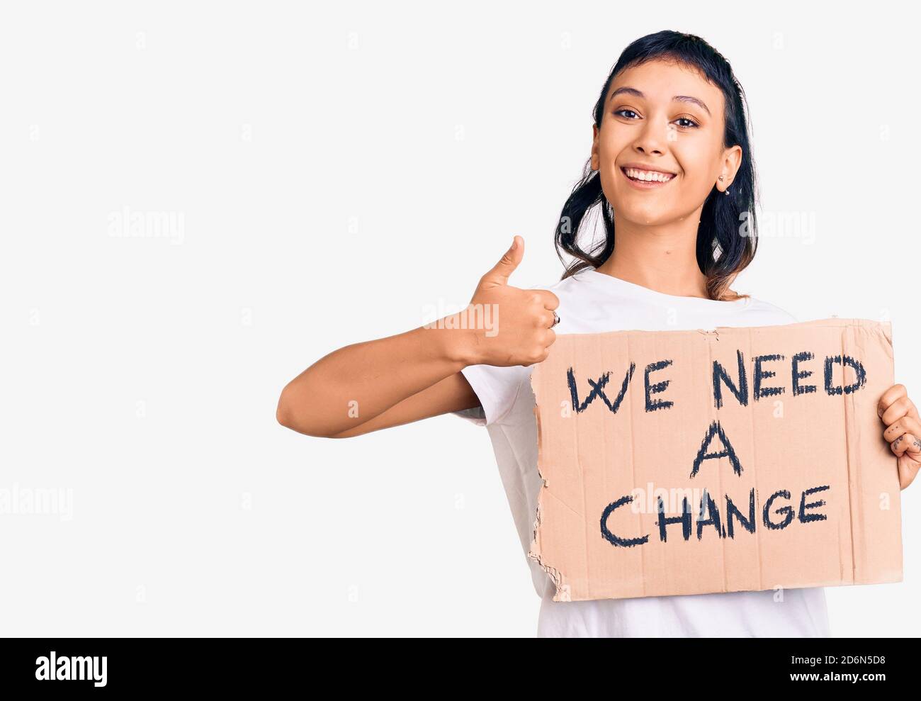 Young woman holding we need a change banner smiling happy and positive ...
