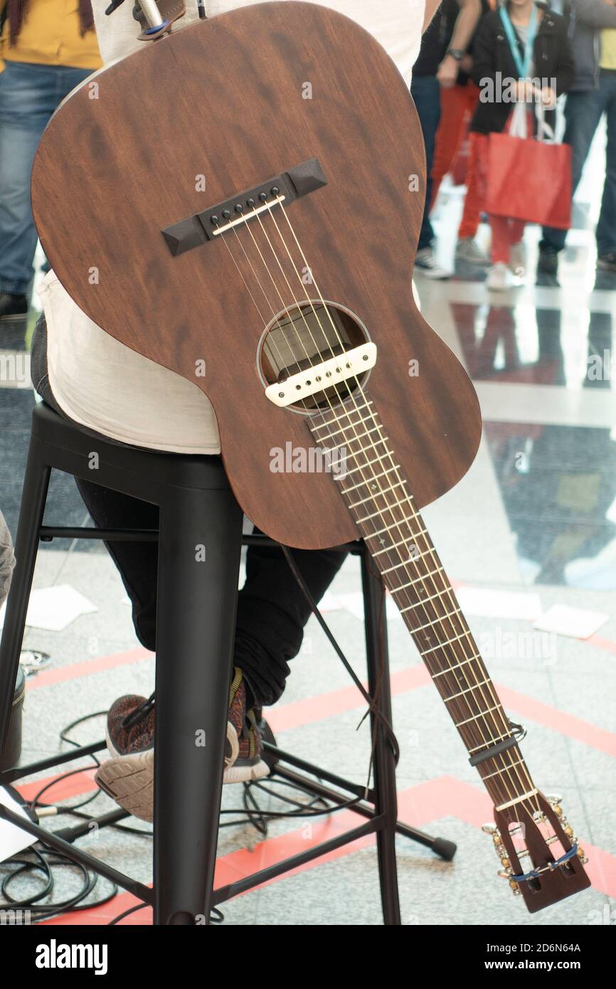 An unrecognizable guitarist with an acoustic guitar haning on his back ...