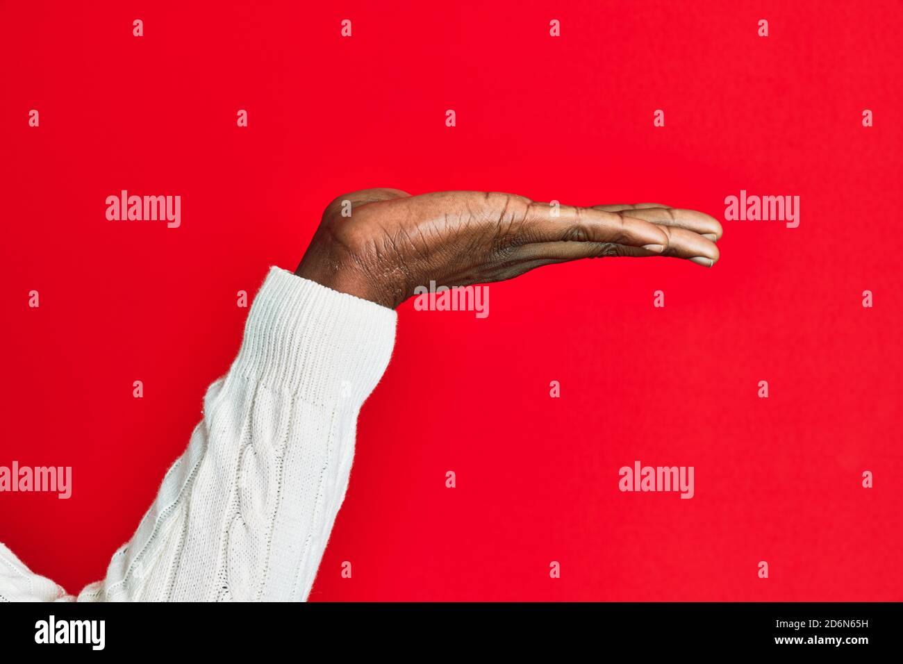 Arm and hand of african american black young man over red isolated ...