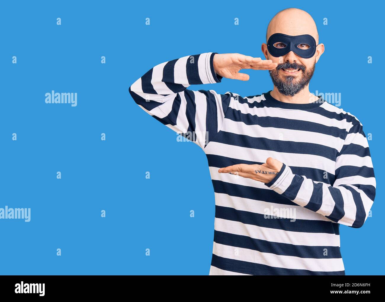 Young handsome man wearing burglar mask gesturing with hands showing ...