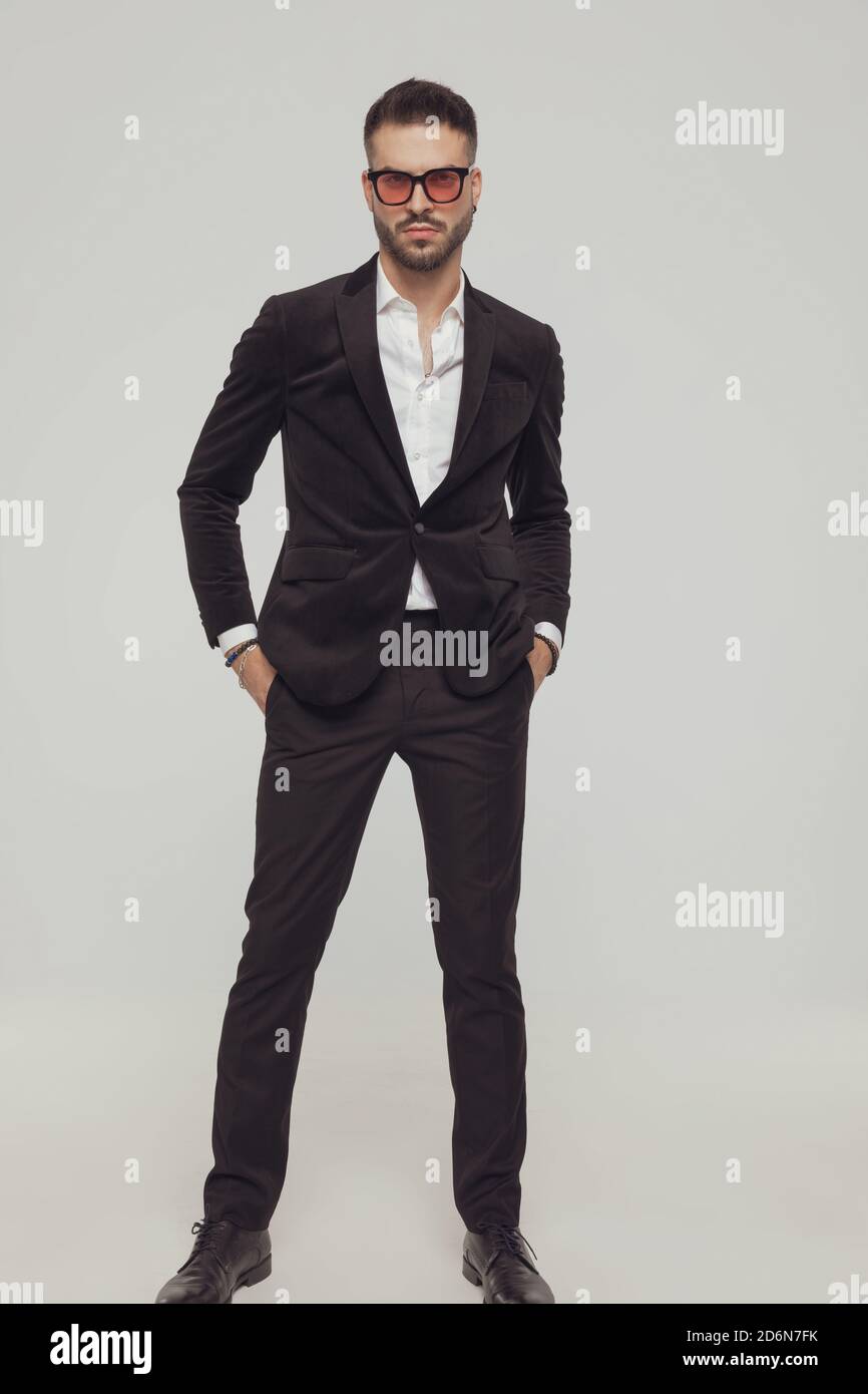 Serious fashion model holding both hands hand in pockets while standing ...