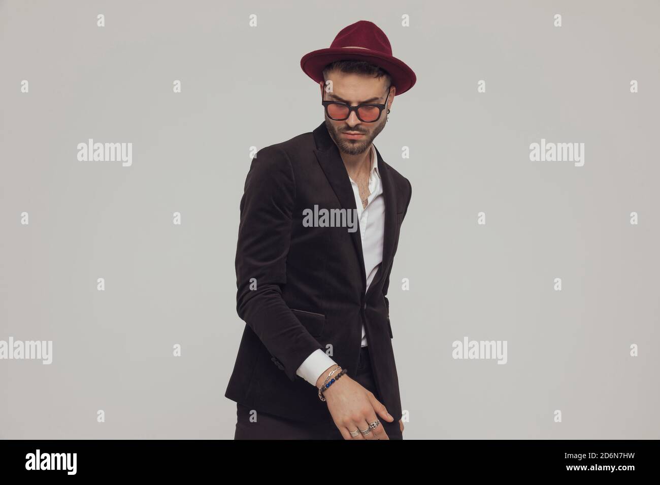 Thoughtful fashion model looking down, wearing hat and sunglasses while ...