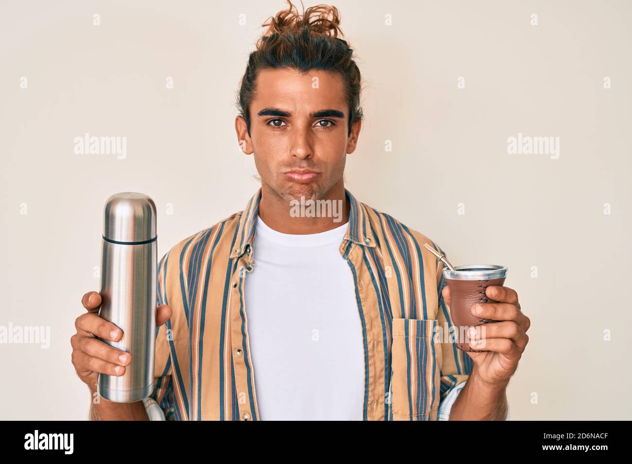 Young hispanic man drinking mate infusion depressed and worry for ...