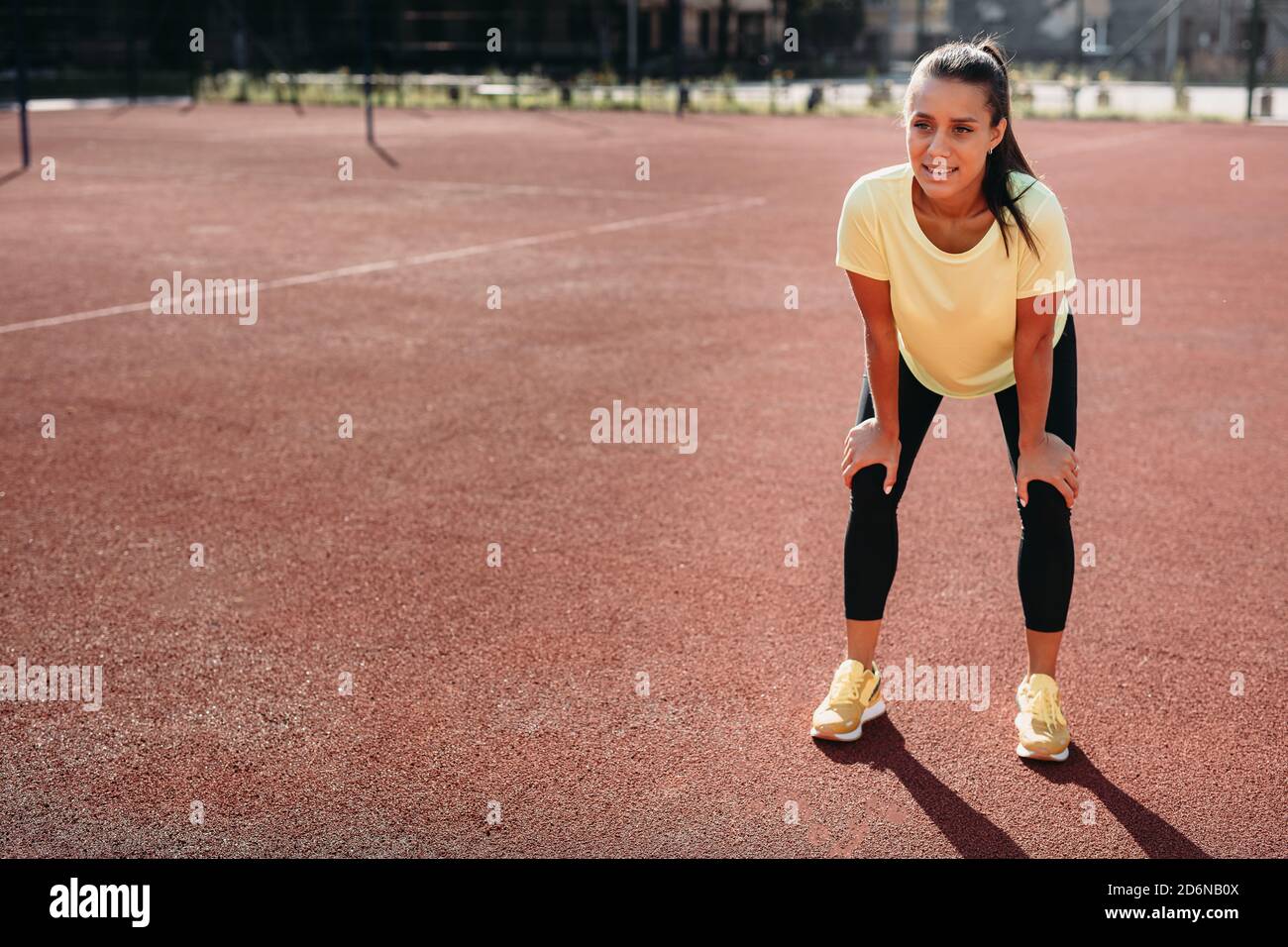 Female athlete resting with hands on knees after run Stock Photo - Alamy